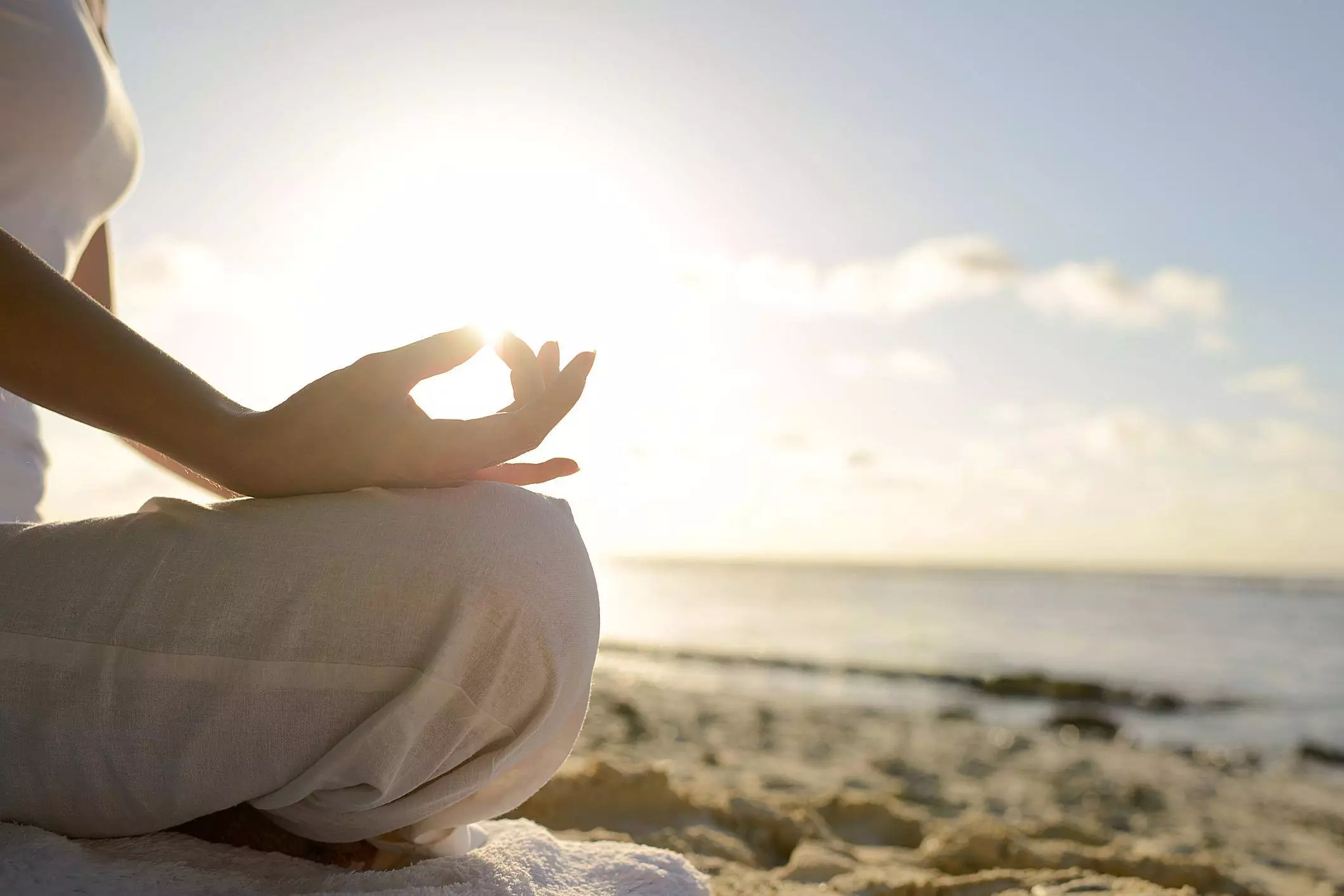 Frau sitzt am Strand mit Yoga-Lotus-Position