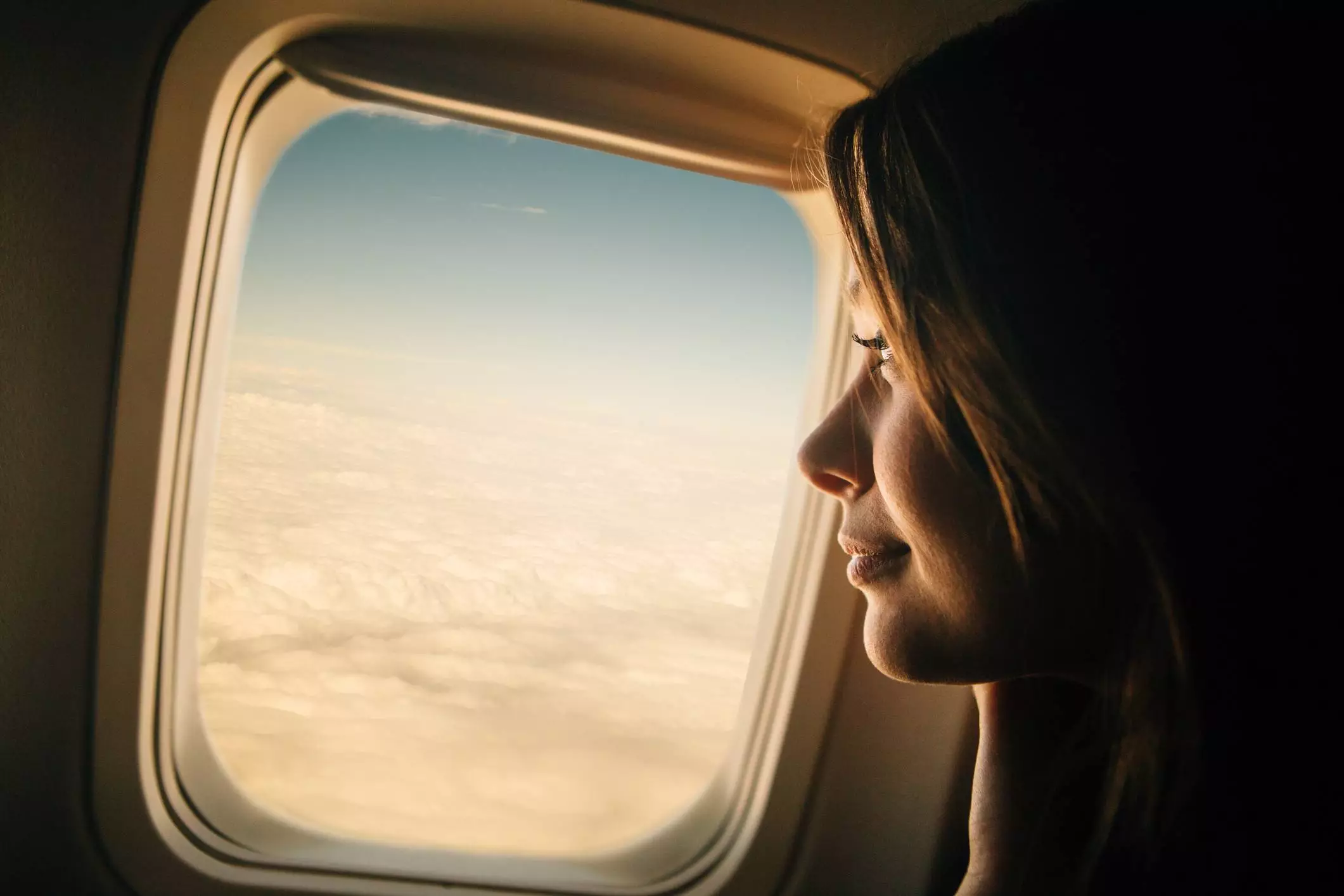 Mujer mirando kwa ventana de avión.