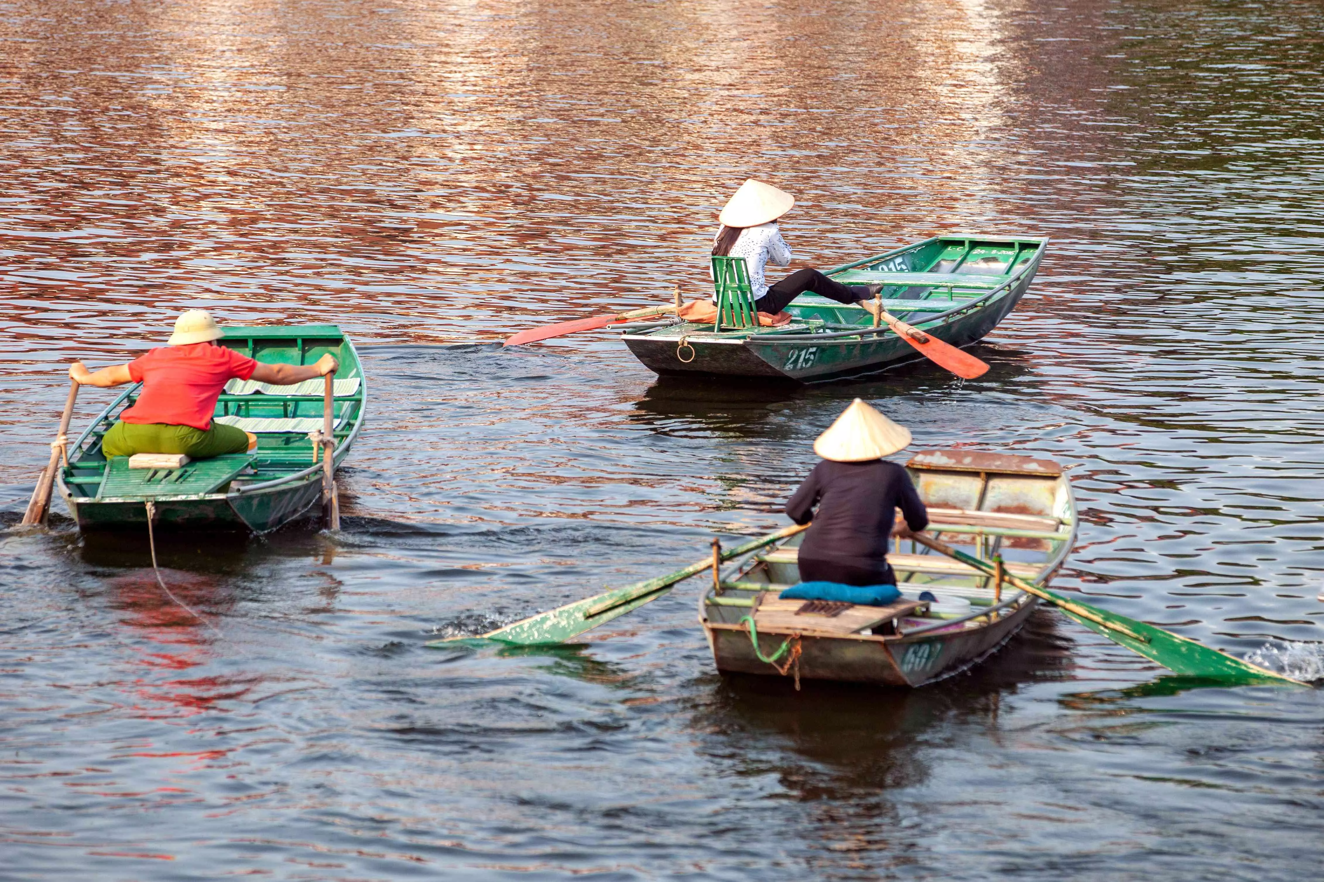 Los remeros en botes de remos simples en Vietnam atraviesan el delta del río Rojo