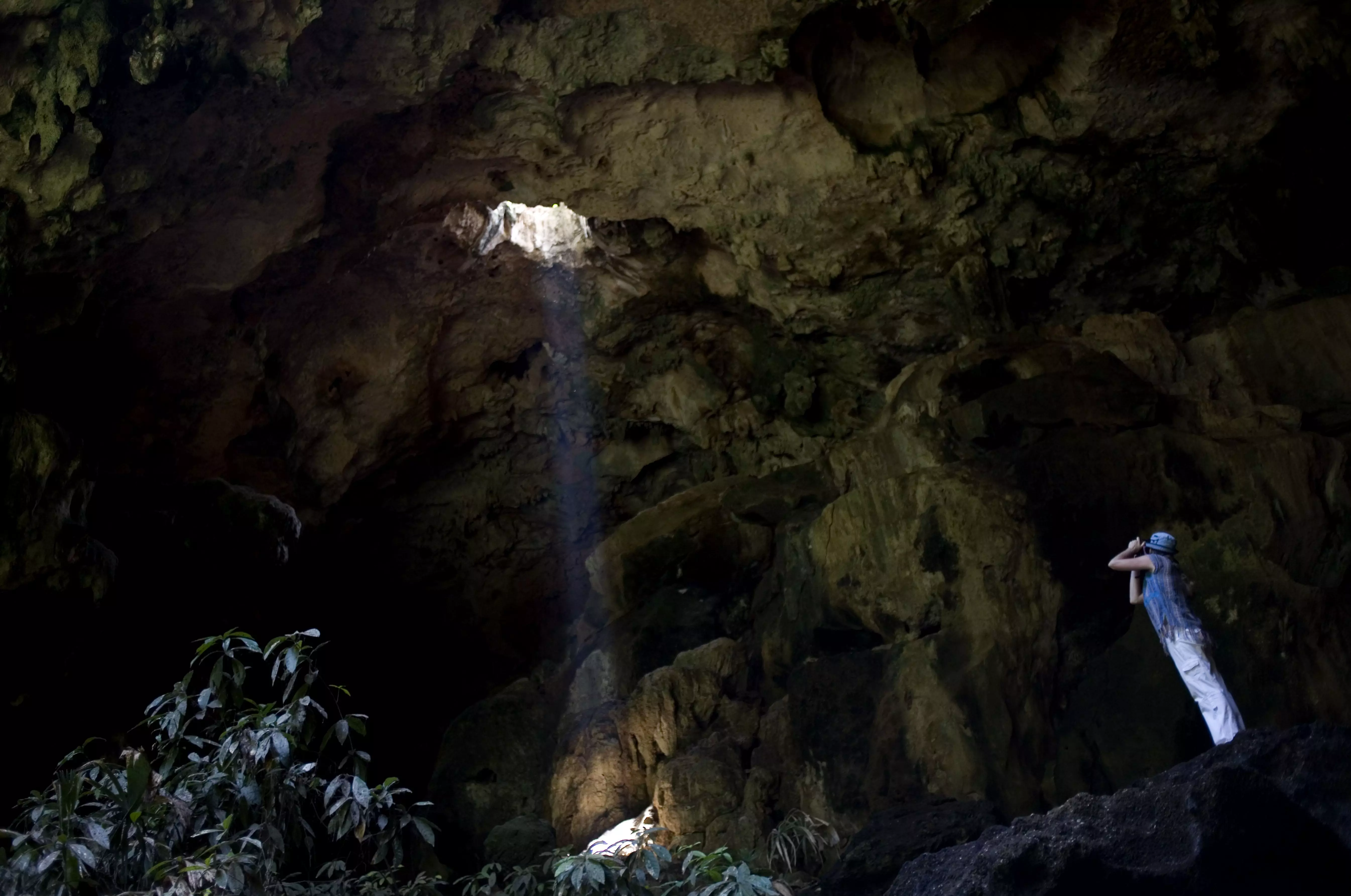 'n Toeris neem foto's by die ingang van die Calcehtok-grot in Oxkintok, Yucatan-staat op Mexiko se Yucatan-skiereiland.