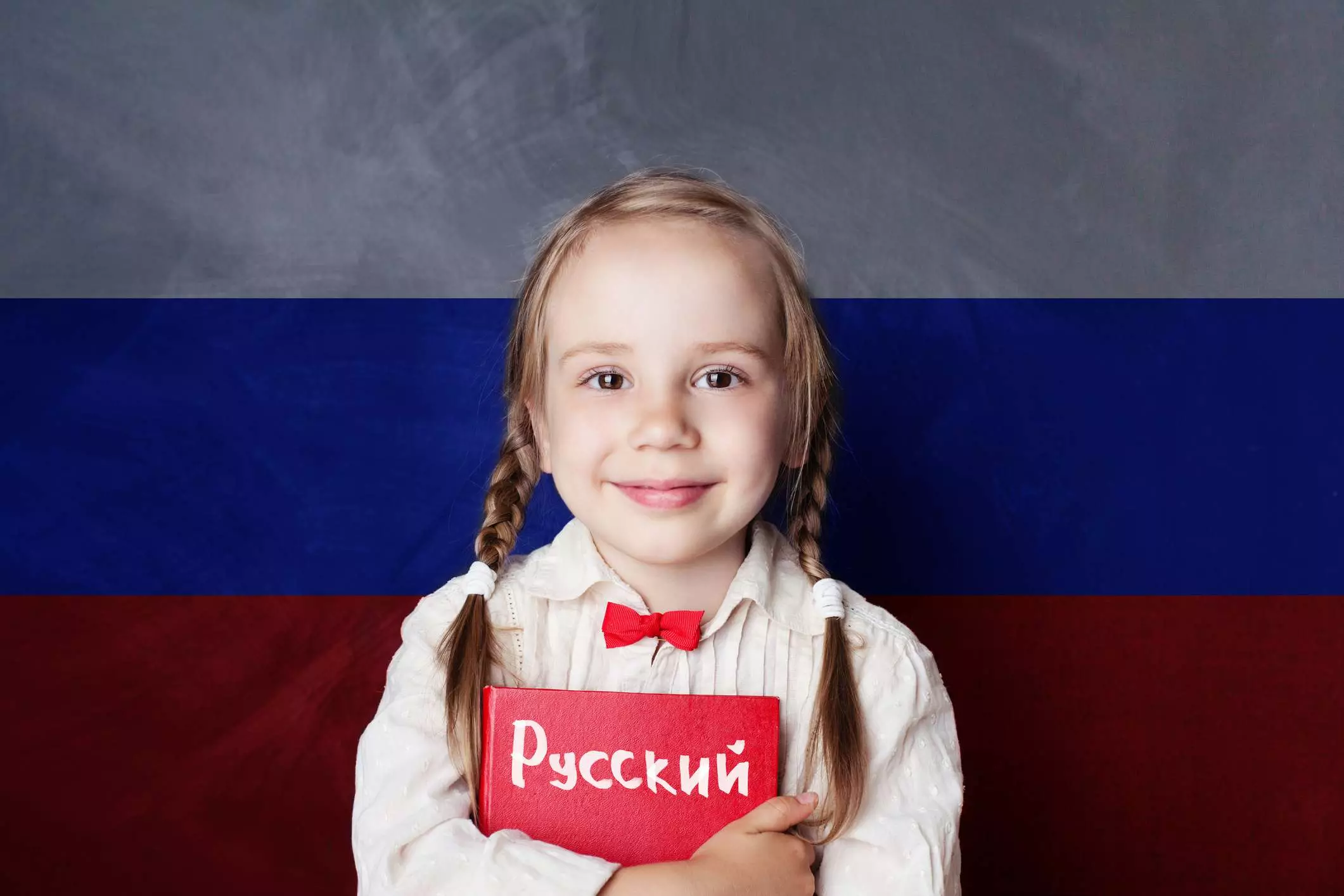 Belajar bahasa rusia. Pelajar perempuan kanak-kanak dengan buku dengan latar belakang bendera russian