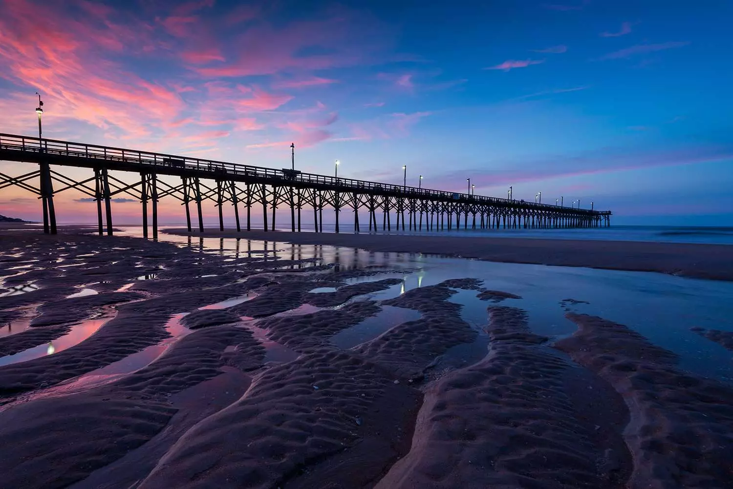 matahari terbit di pantai di dermaga kota selancar di Surf City, NC