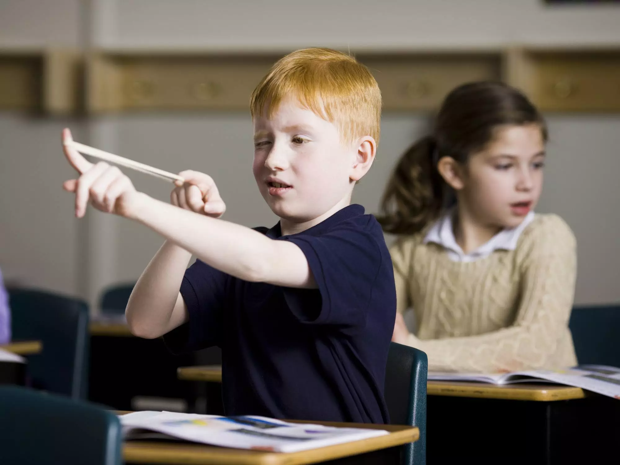 Neno sentado na mesa da escola apuntando a unha goma