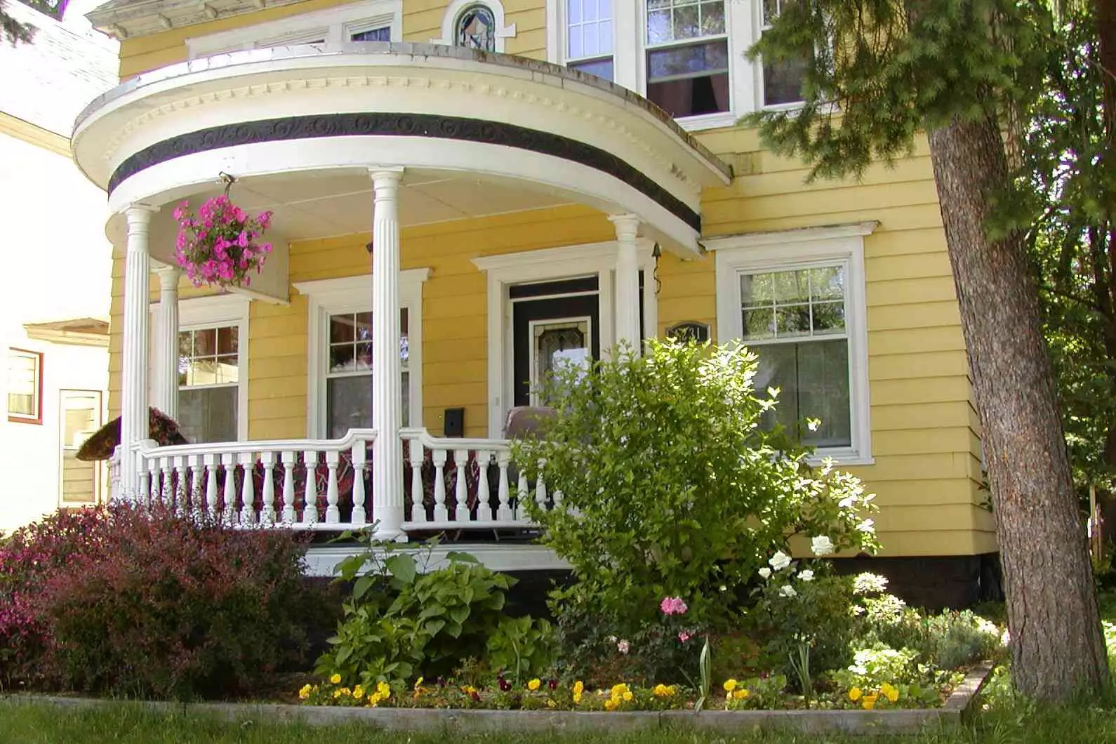 Dorski stupovi na okruglom trijemu pričvršćenom na pročelje žute kuće