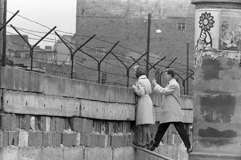 Mlada žena, u pratnji svog dečka, nesigurno stoji blizu vrha Berlinskog zida kako bi razgovarala sa svojom majkom na strani istočnog Berlina.