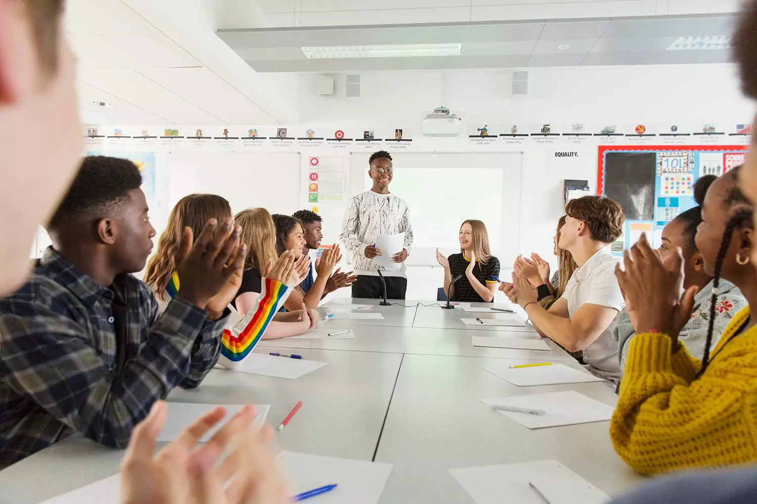 Alumnos de secundaria aplaudindo ao compañeiro na clase de debate