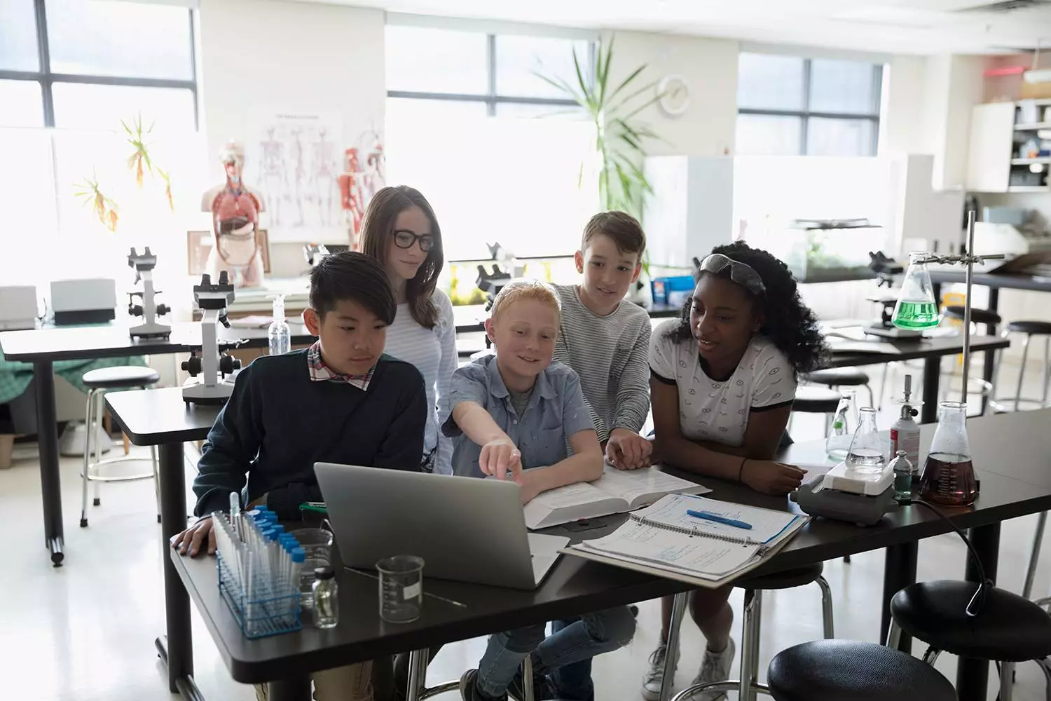 Studenti delle scuole medie che conducono esperimenti scientifici al computer portatile nel laboratorio di scienze