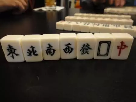 Vind- og dragebrikkene i et Mahjong-sett står oppreist på et bord.