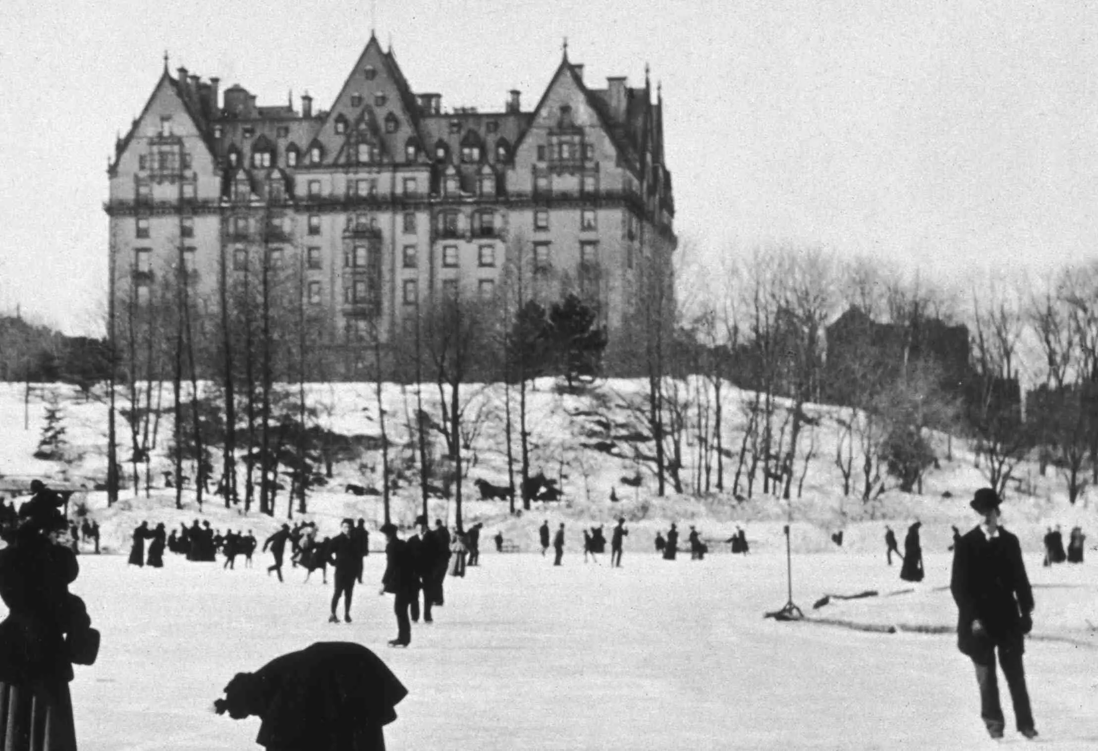 Fọto itan dudu ati funfun ti ile nla ti n wo awọn skaters yinyin ni Central Park, 1894