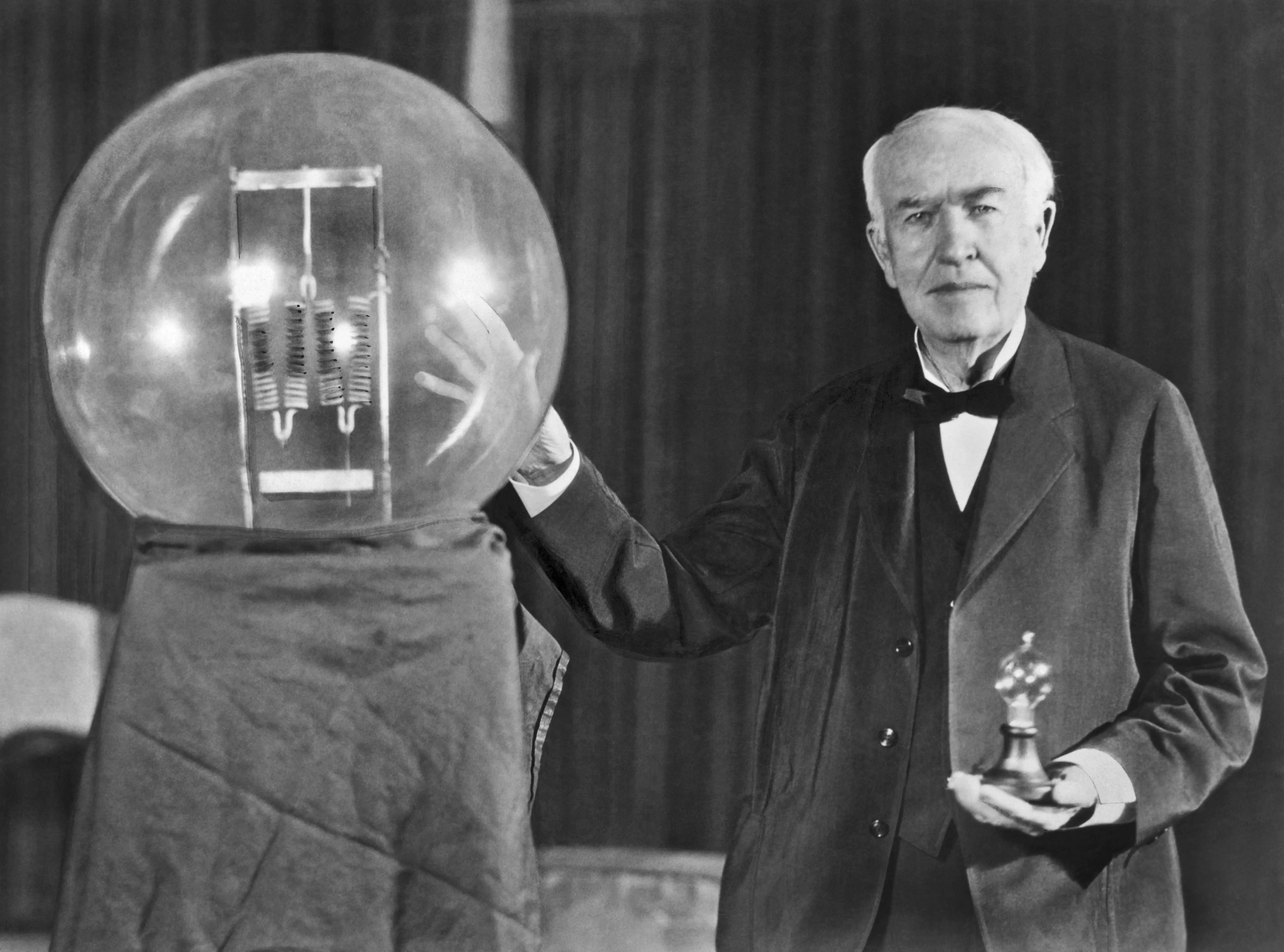 Thomas Edison se tient avec une grosse ampoule.