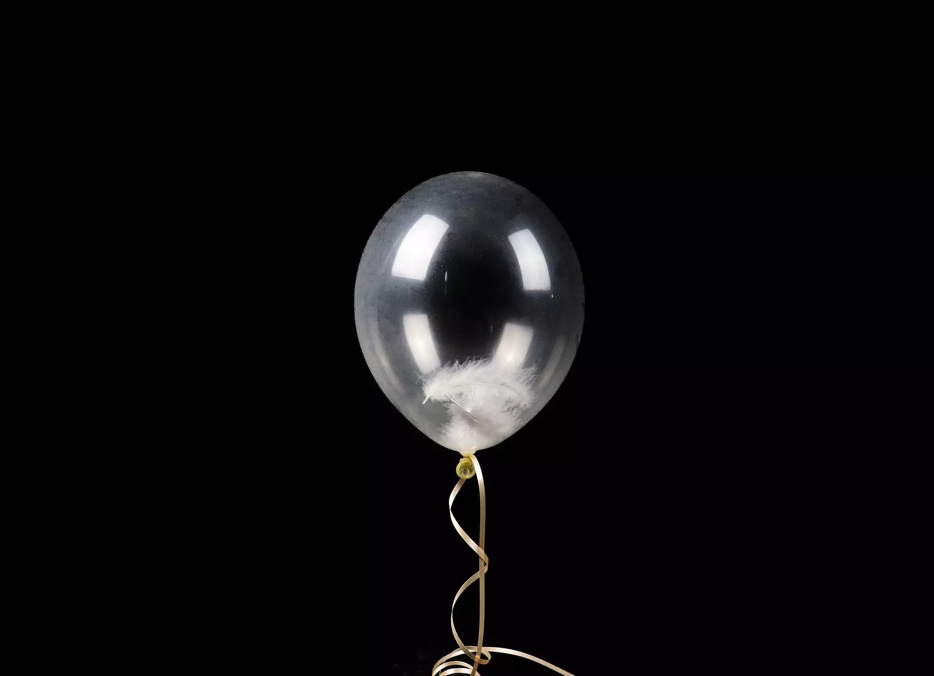 Balon bening berisi helium dengan latar belakang hitam.