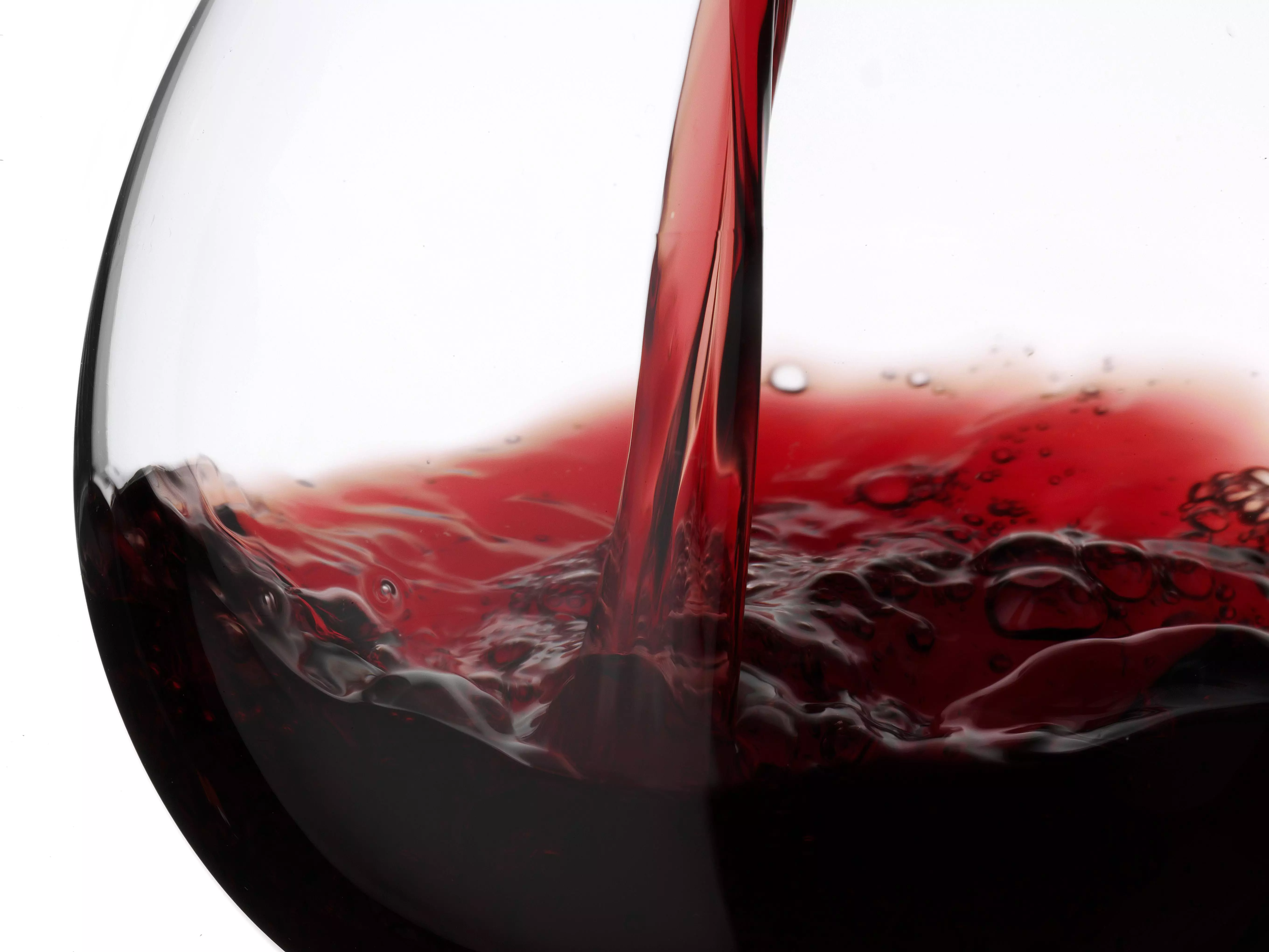 Wein wird in ein Glas auf weißem Hintergrund gegossen.