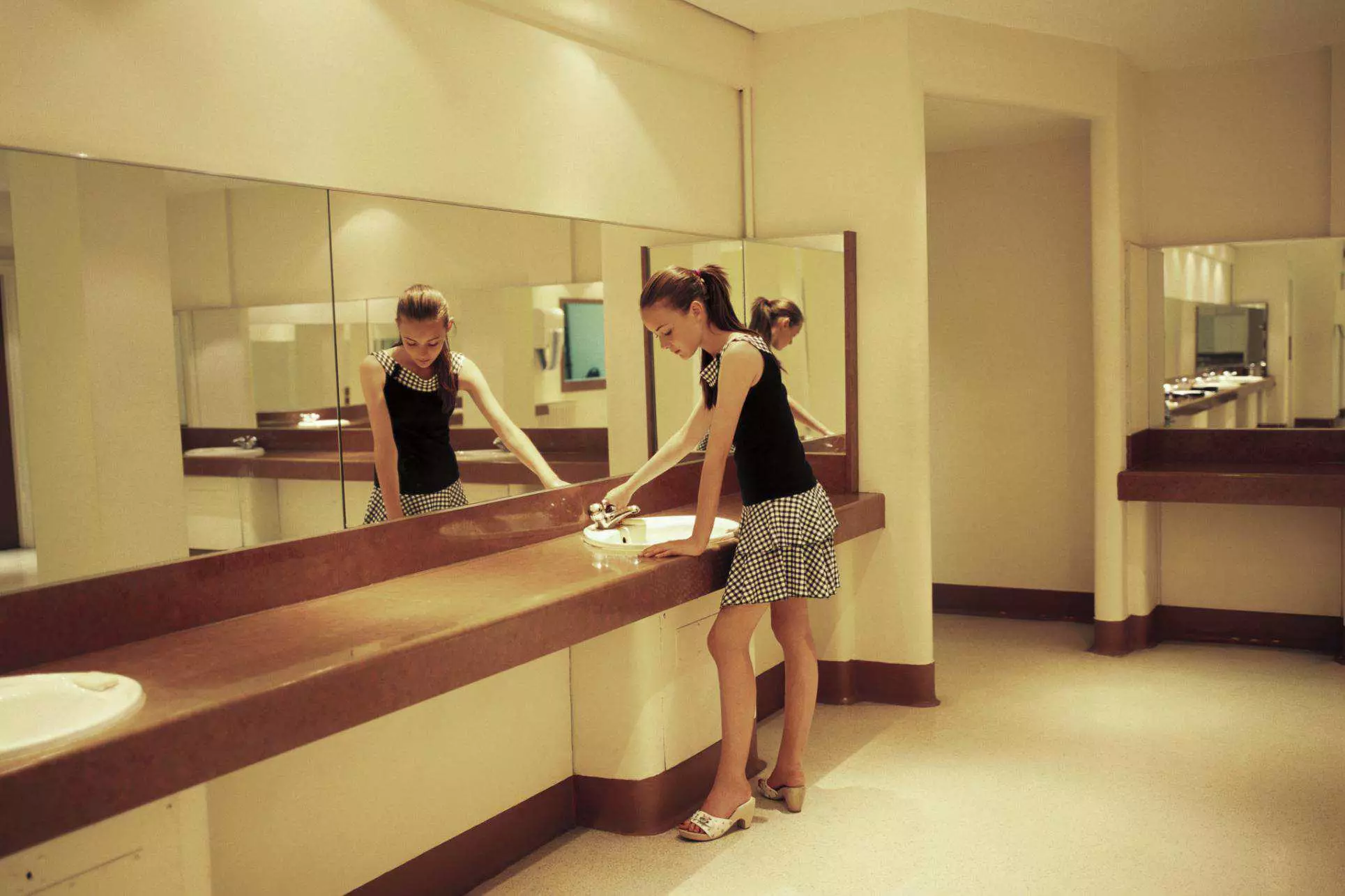 Kız (12-14) lavabonun başında duruyor, musluğu çeviriyor