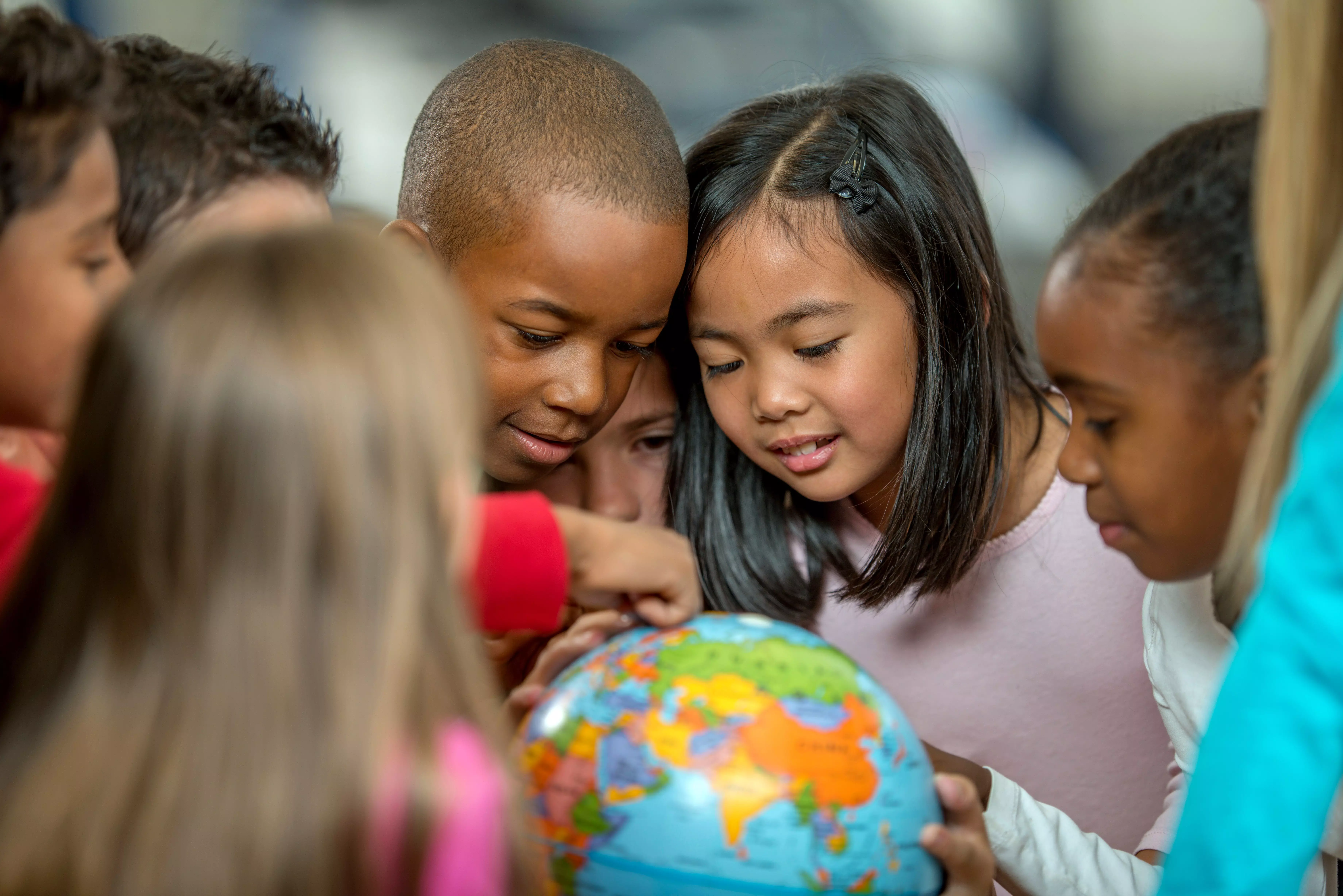 Pelajar sekolah rendah belajar tentang negara dan geografi dengan meneliti glob