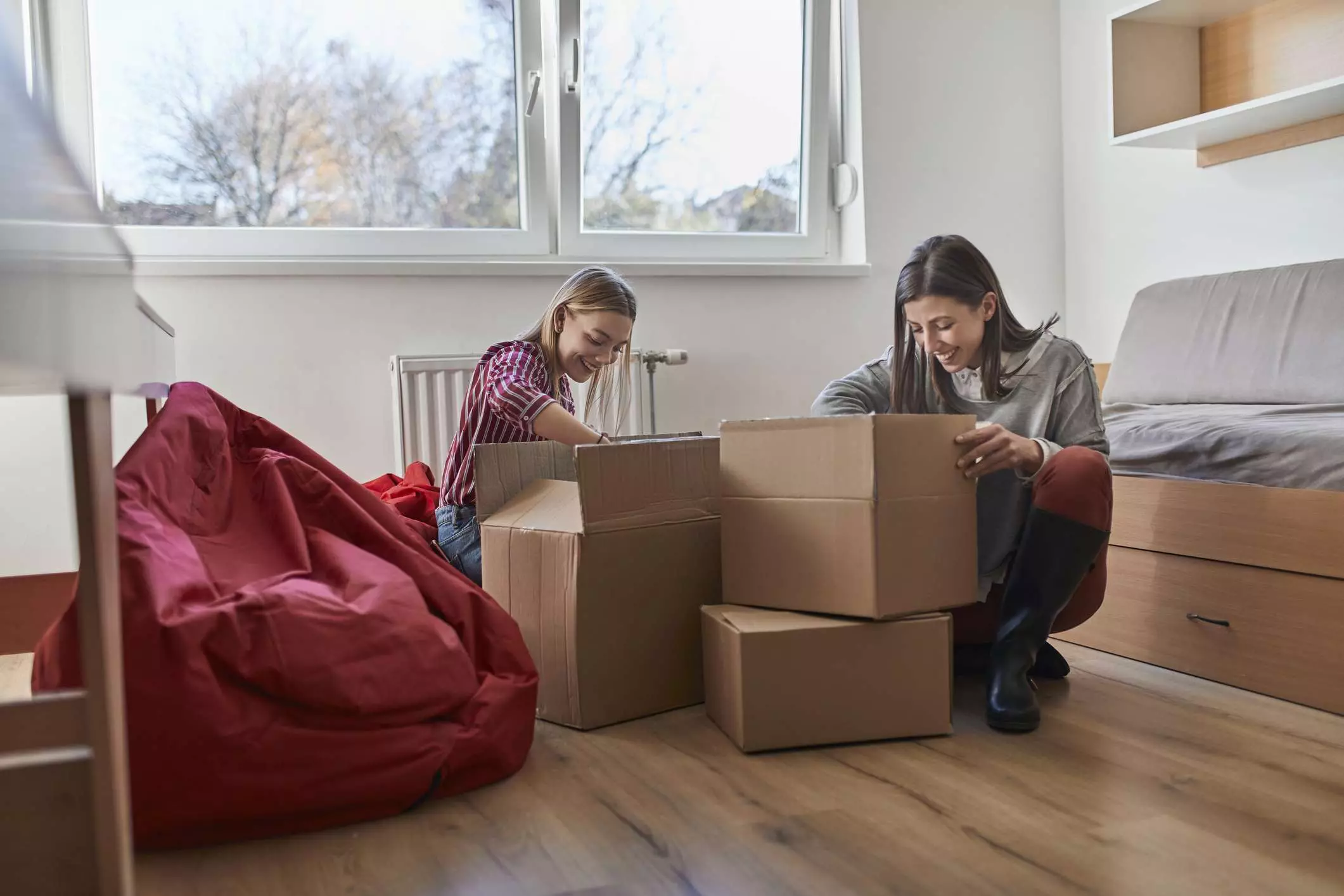 Två unga kvinnor packar upp kartonger i ett rum