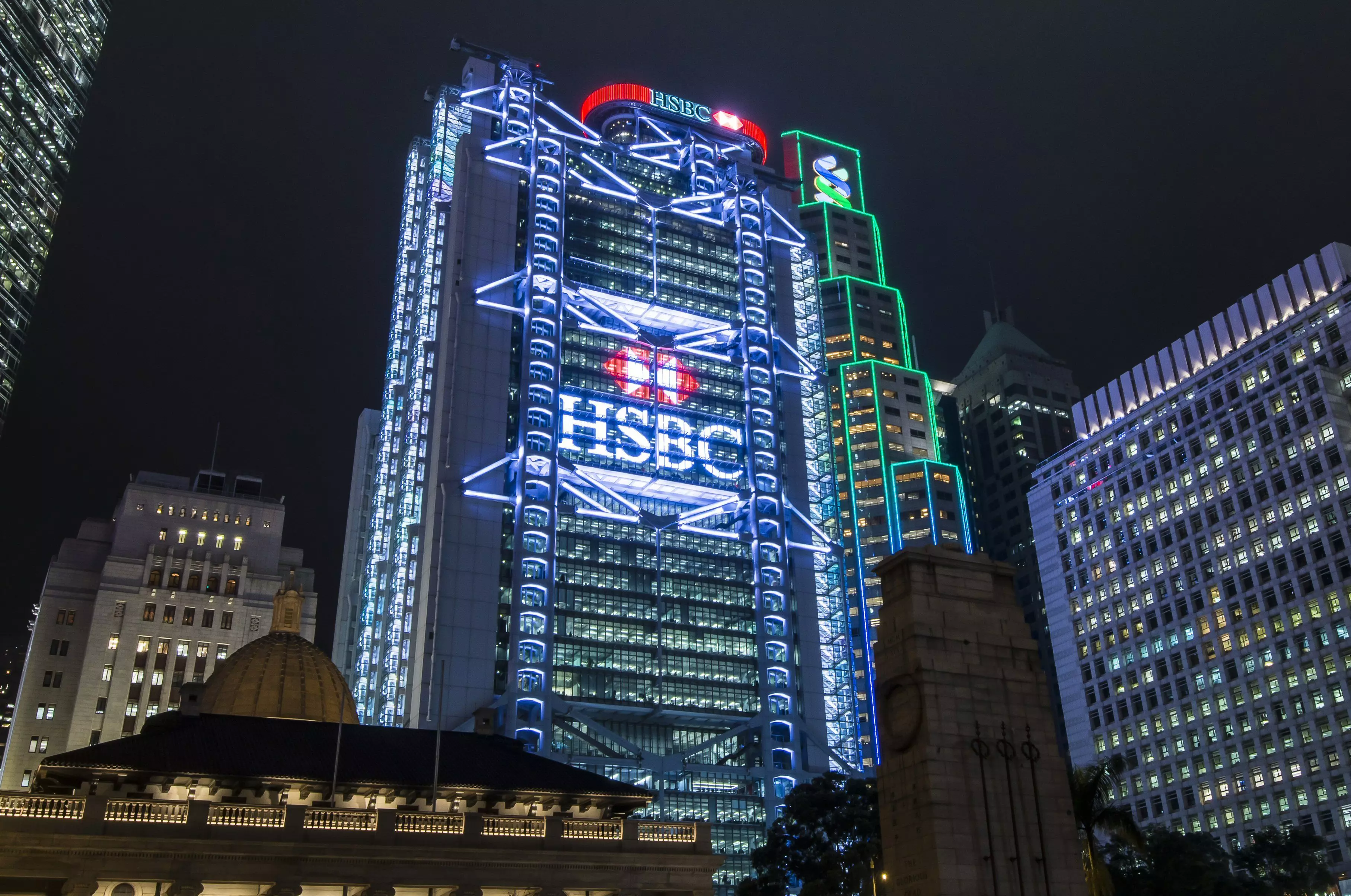 natudsigt over skyskraber oplyst med blåt og grønt lys og HSBC i lys på facaden i midten og på toppen