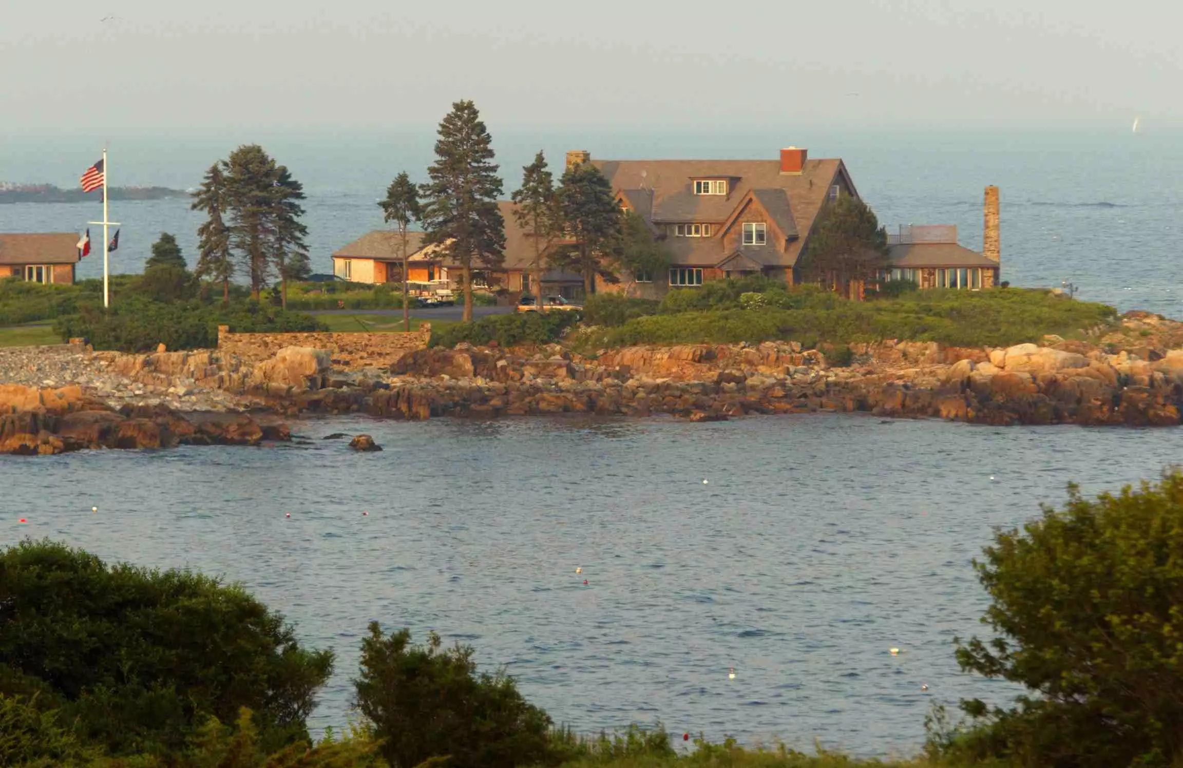 casa de madeira en expansión con gran tellado nun anaco de terra rochosa case rodeada de auga