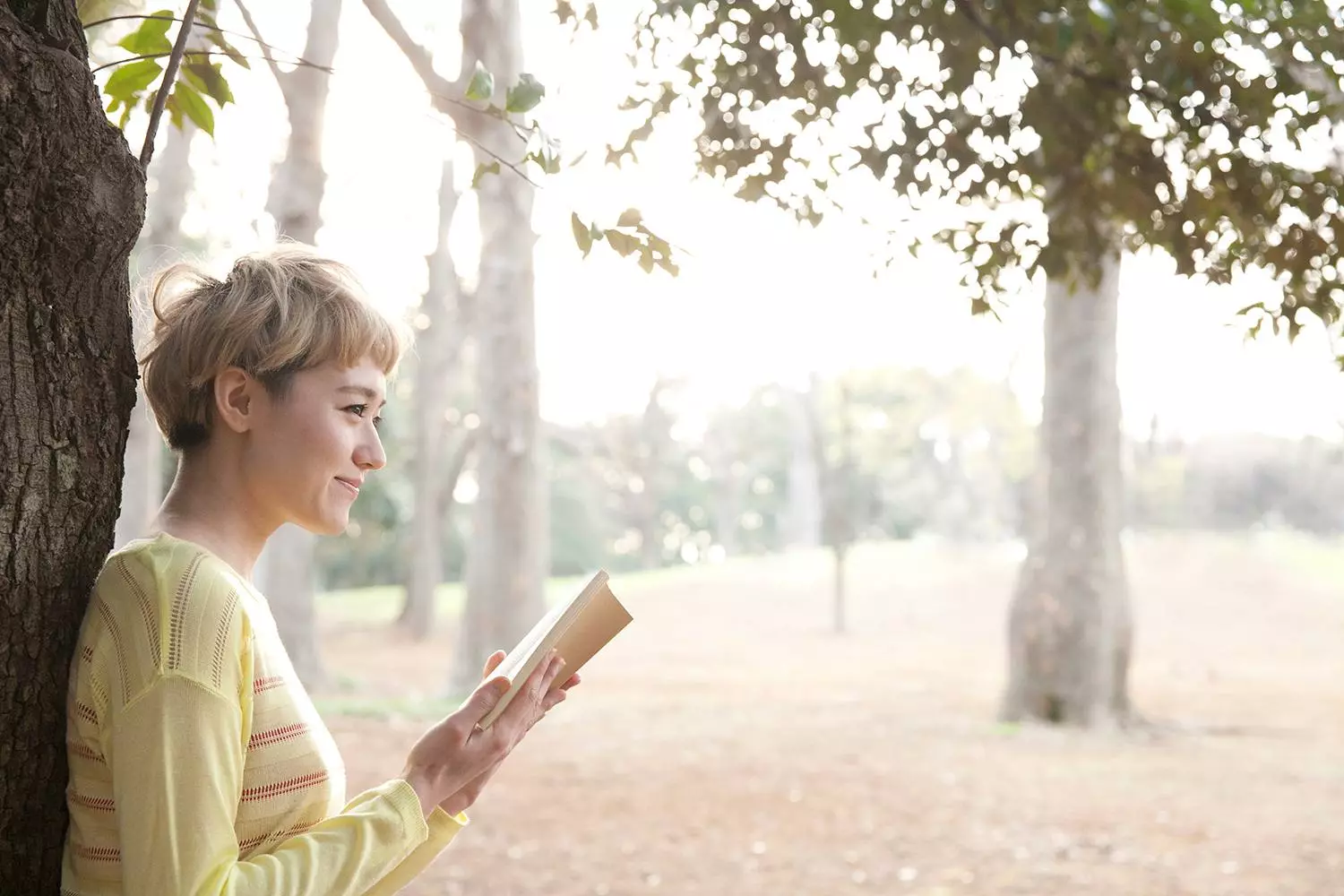 Модна японська жінка читає книгу в парку.
