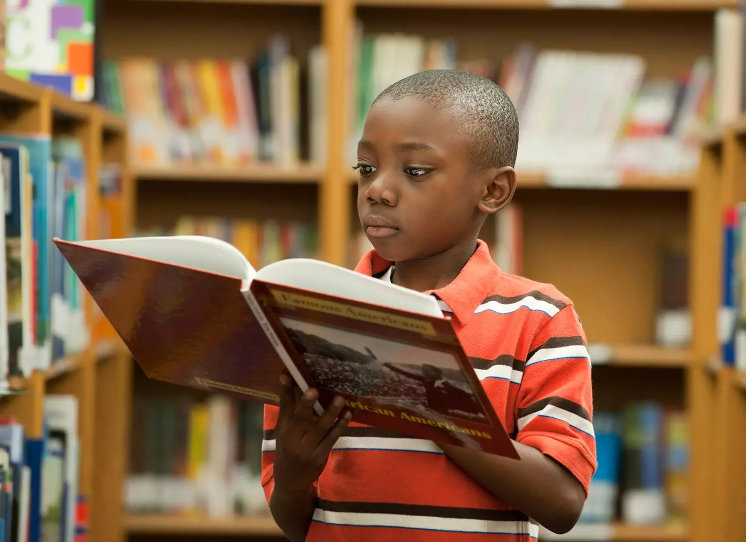 Swart seun lees boek in biblioteek