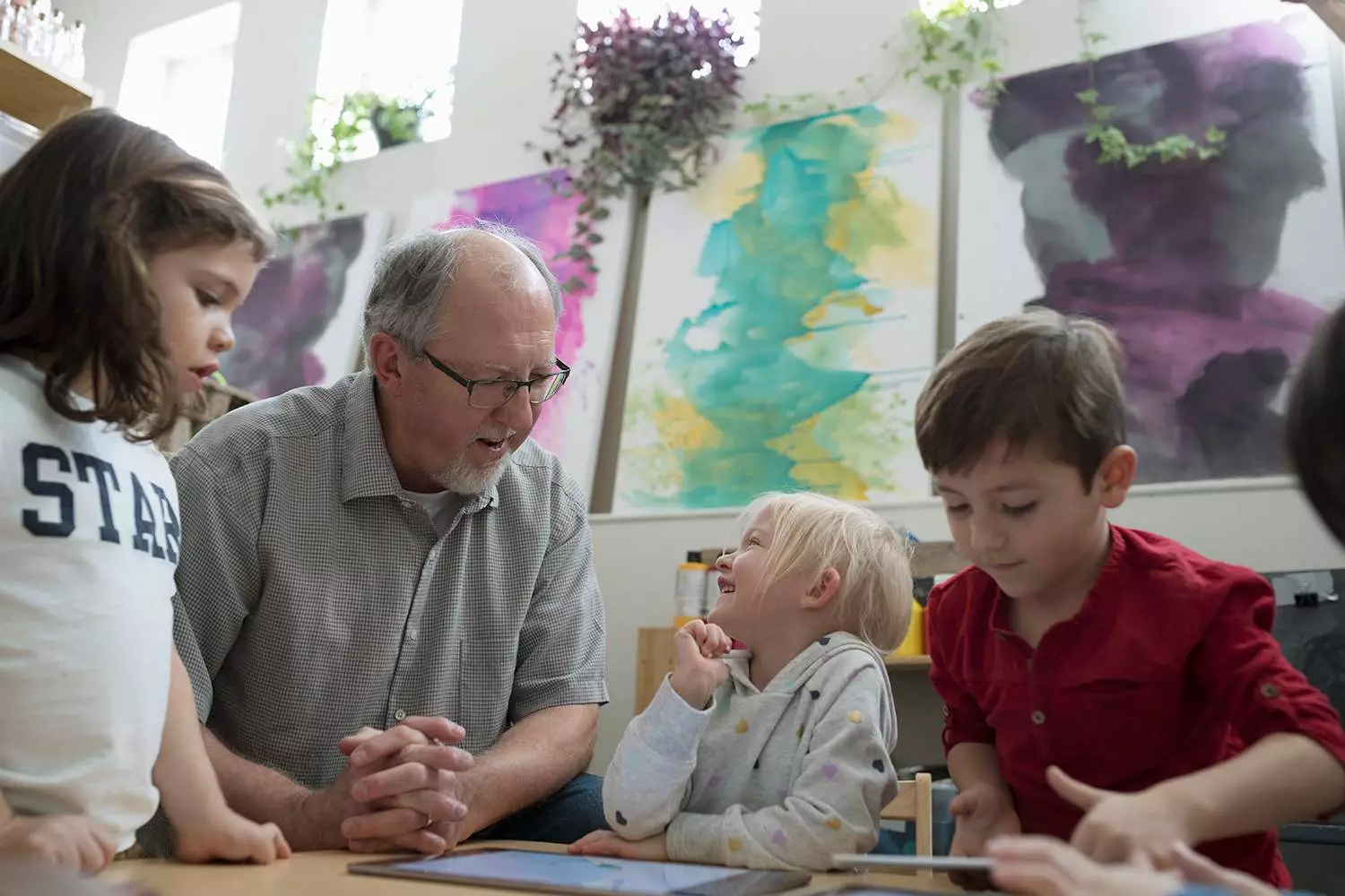 Senior frijwilligers en foarskoalske studinten dy't digitale tablet brûke yn 'e klasse