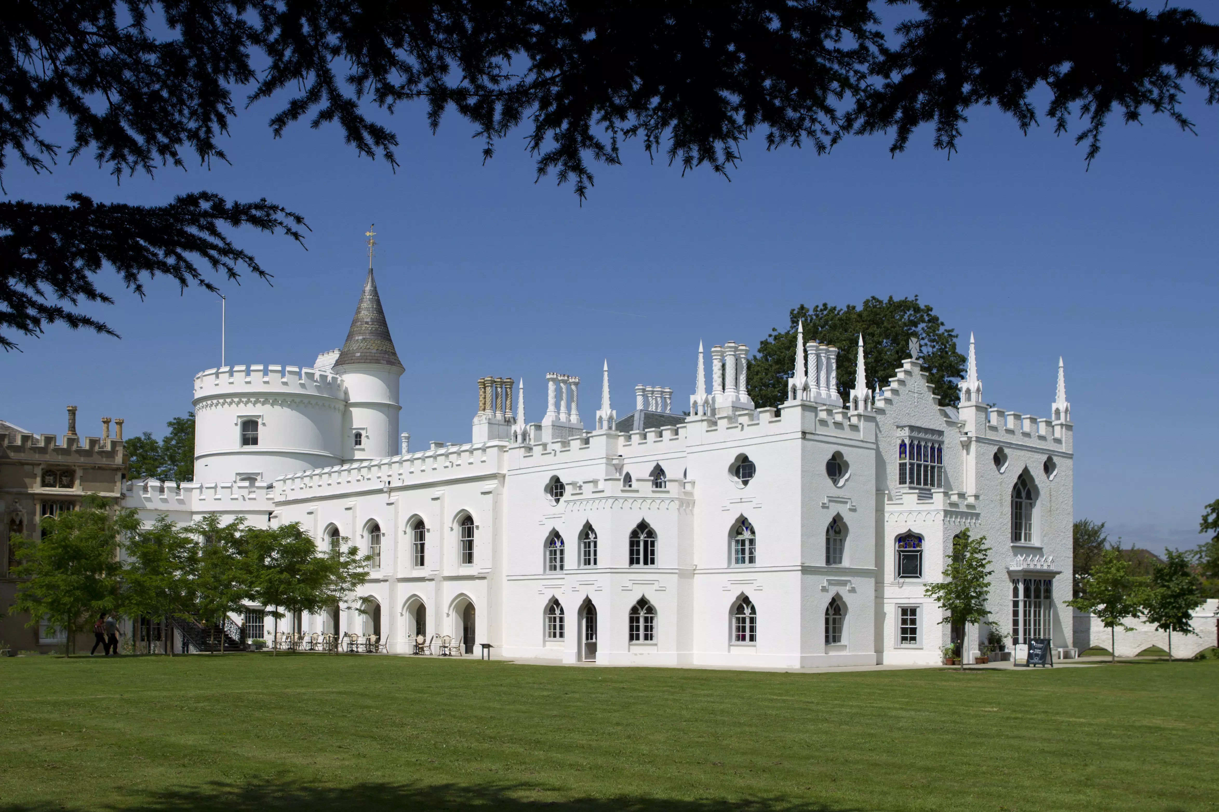 didelė balta pilis primenanti rezidencija su arkiniais langais, parapetais, bokšteliais ir crenalation