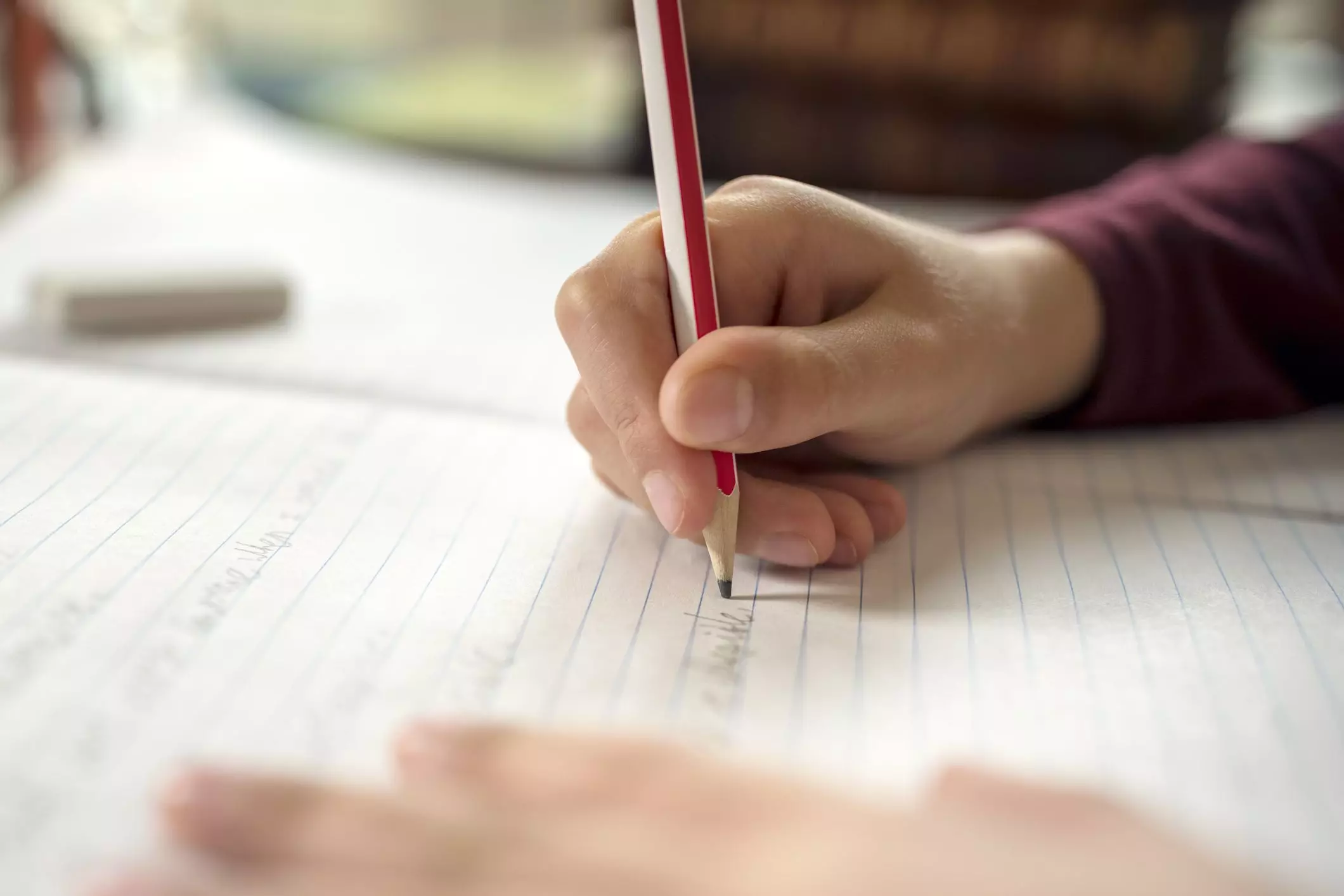 ایک لڑکا اپنے اسکول کا کام کرتے ہوئے نوٹ پیڈ میں لکھ رہا ہے۔