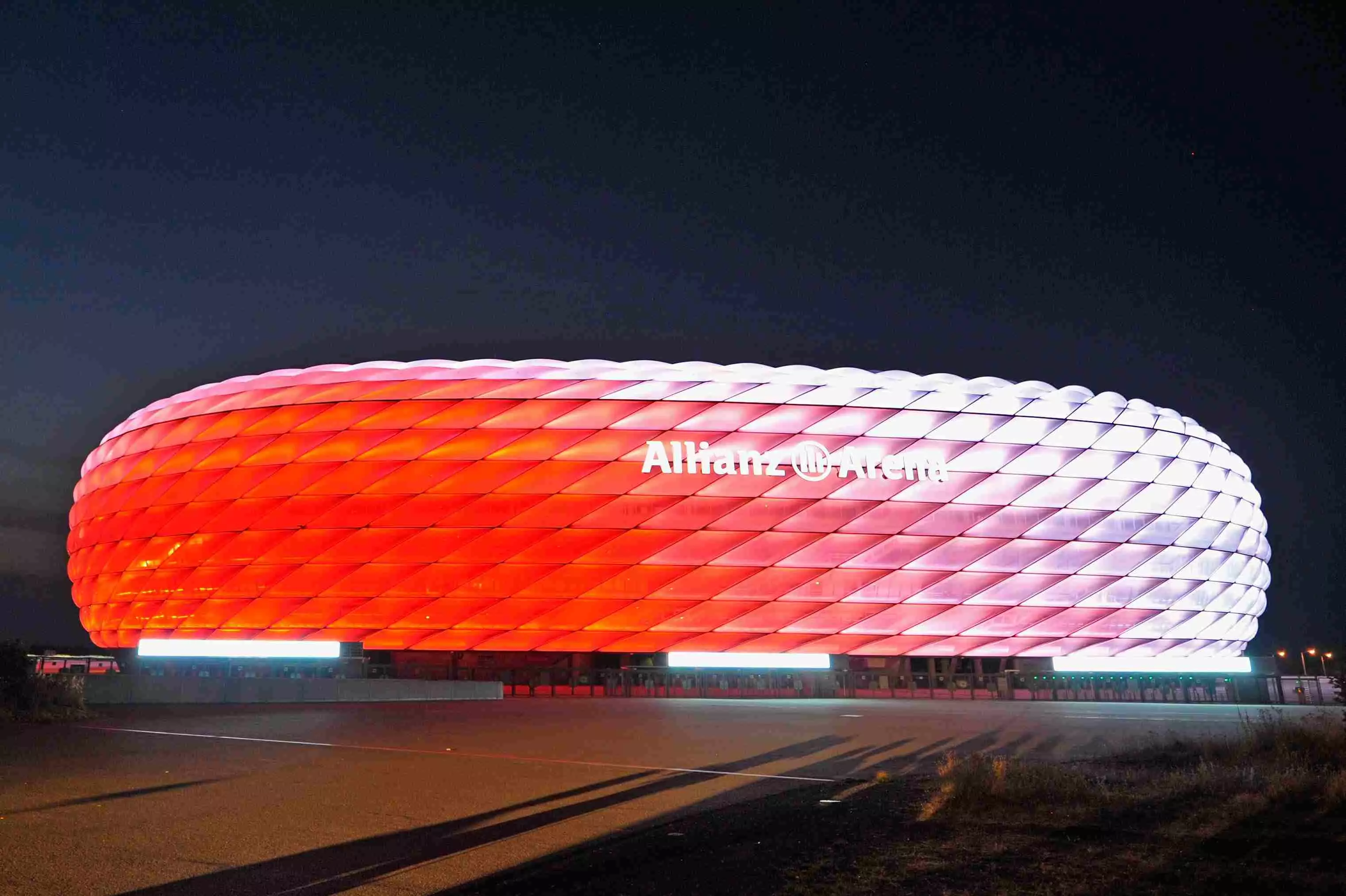branco durante o dia, o exterior esculpido da Allianz Arena brilha em vermelho à noite