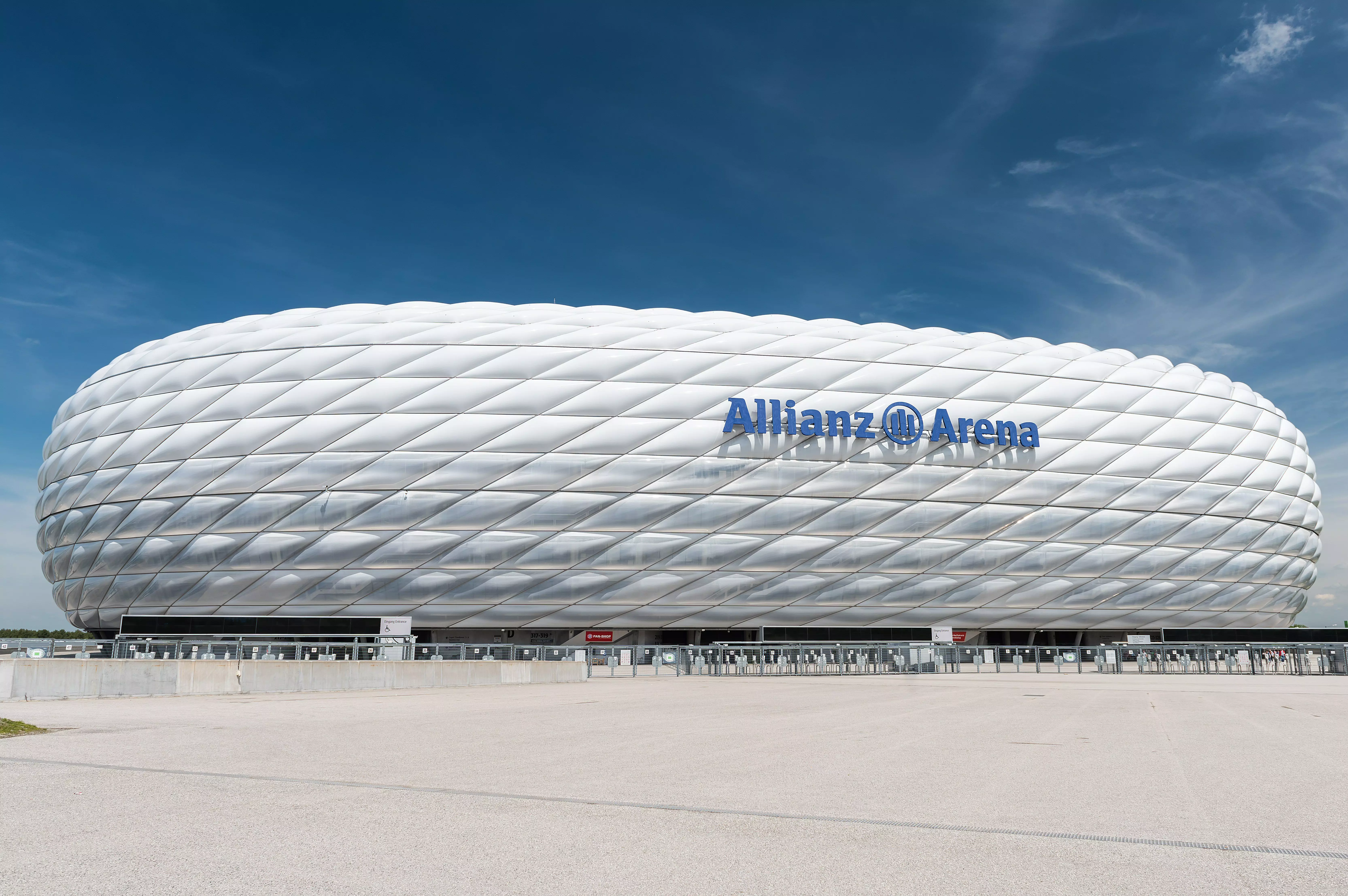 نمای جانبی استادیوم ورزشی منحنی، نمای بیرونی مجسمهسازی شده از پانلهای پلاستیکی بادشده ETFE، شبیه یک تایر آجدار سفید در کناره آن