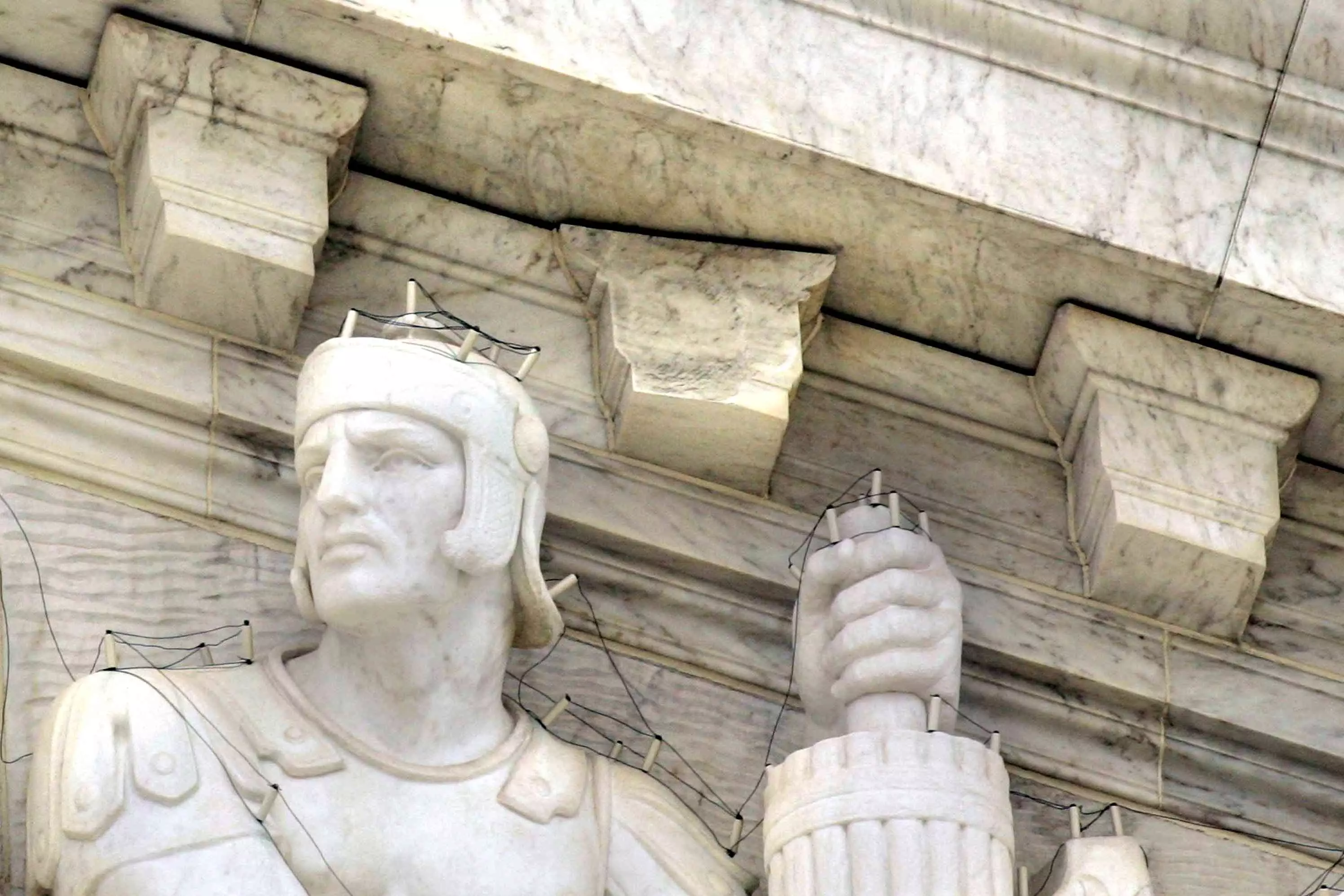 Der gebrochene Zahn und das Netz um Statuen auf dem Gebäude des US Supreme Court