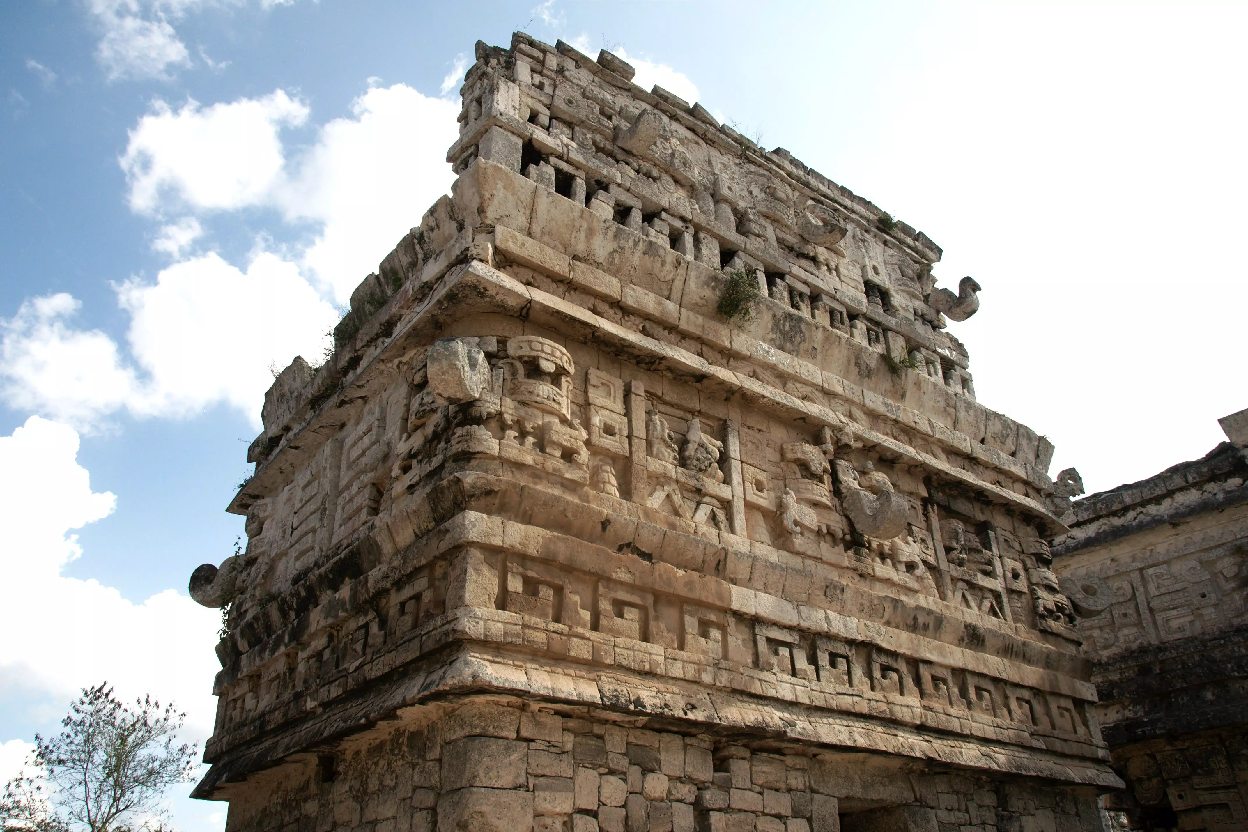 La Iglesia (de kerk) reikt tot in de lucht, versierd met Chac-maskers op de Maya-site van Chichén Itzá