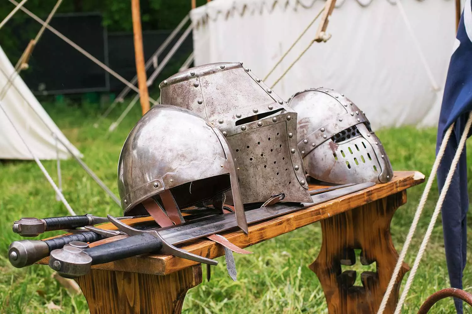Крупни план средњовековних шлемова и мачева на столу.