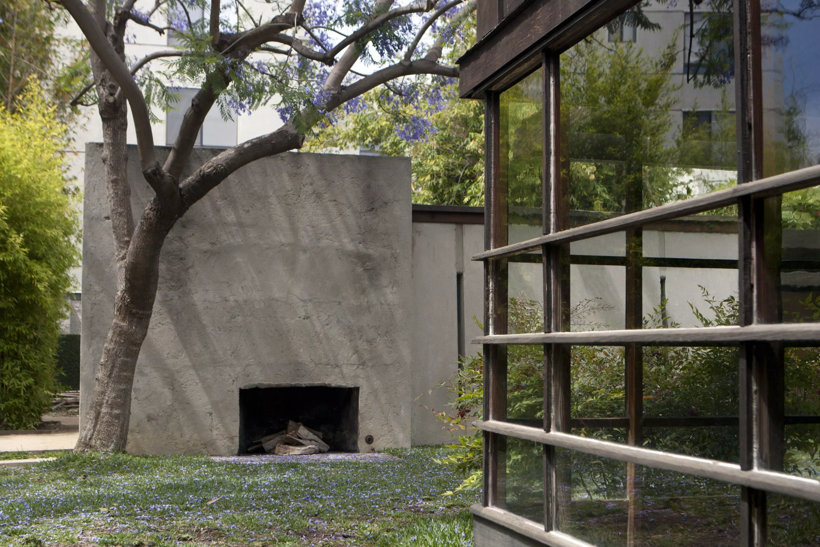 En utendørs peis i en betongvegg overfor en vegg av vinduer