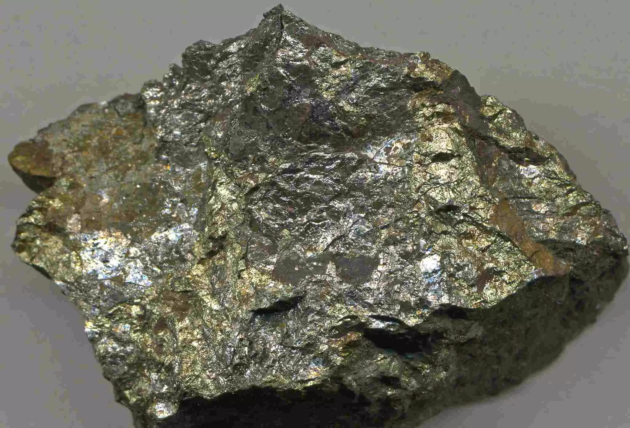 Ang tipak ng chalcopyrite ay malapitan sa isang kulay-abo na background.