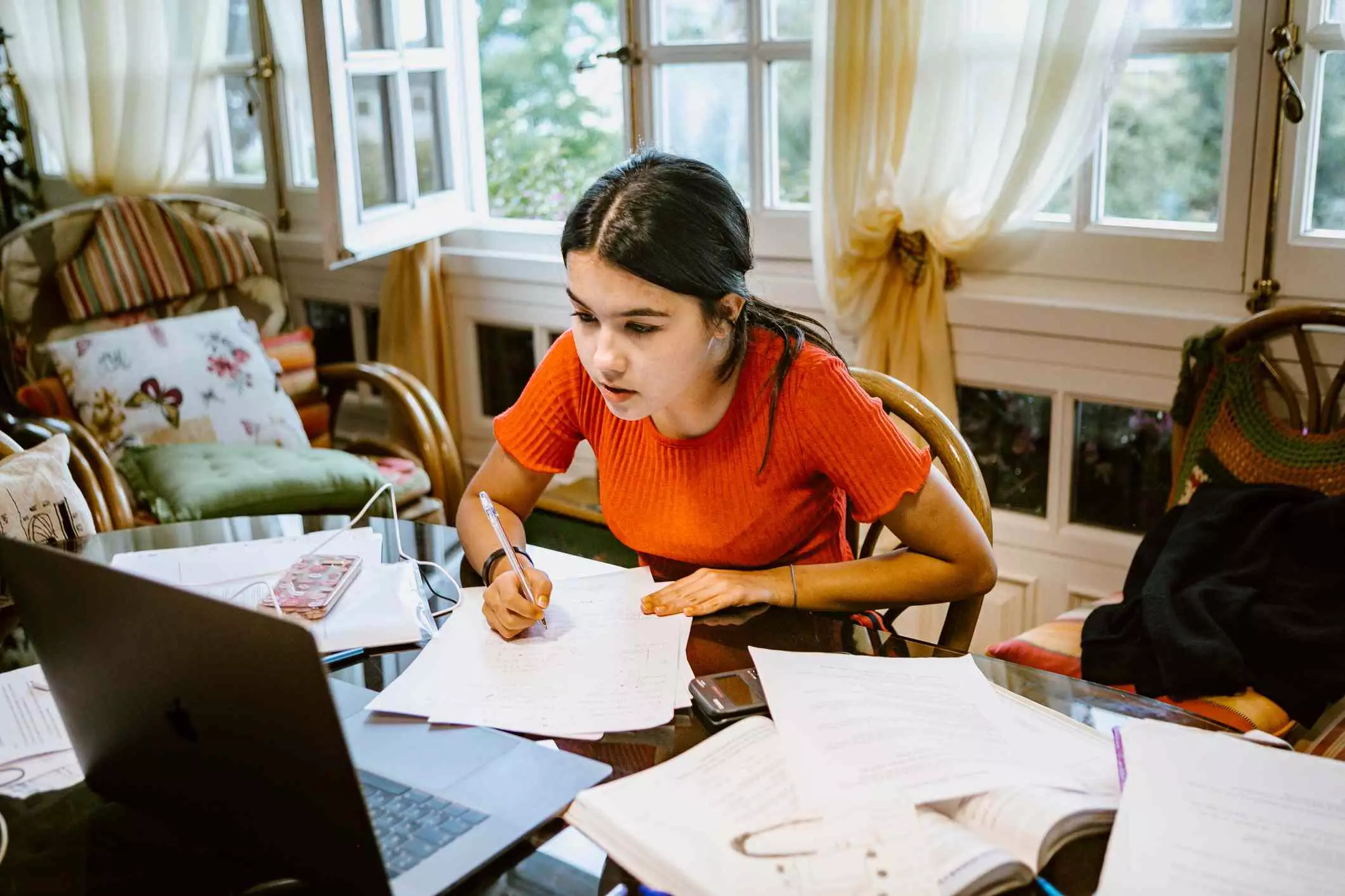 Xwendekarê zanîngehê yê Hispanîkî ku ji malê bi laptopê re hin karên malê dike