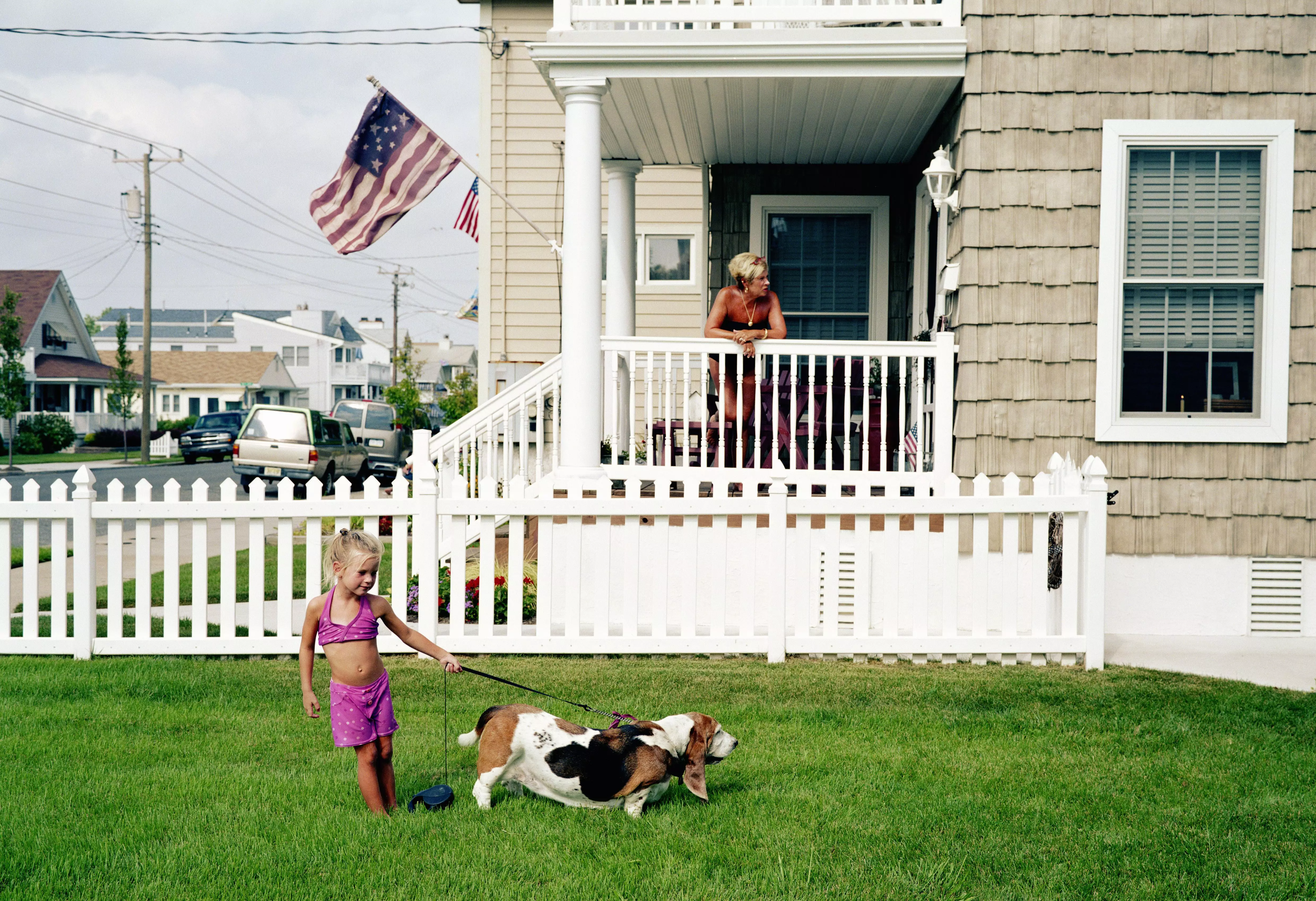 Niña con perro delante de su casa. Bandera meiriceánach ach amháin