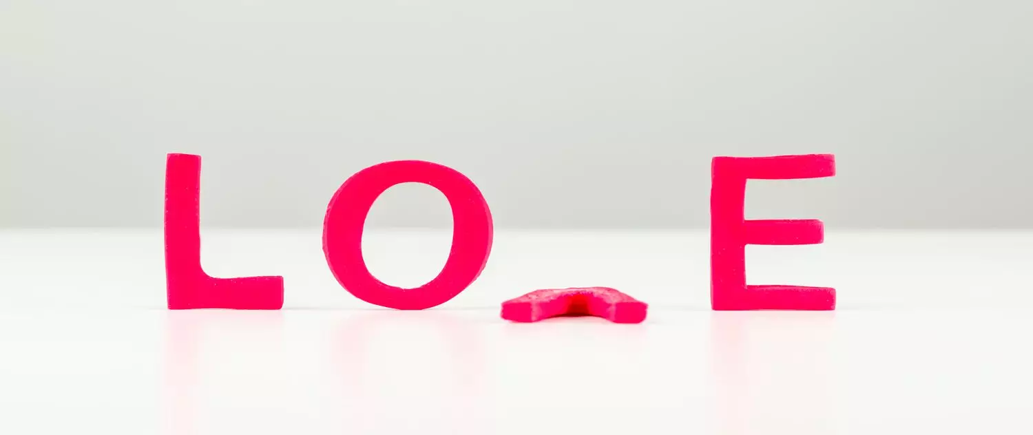 Концептуално изображение с дума любов с червени букви с V, лежащо с лице надолу на масата.