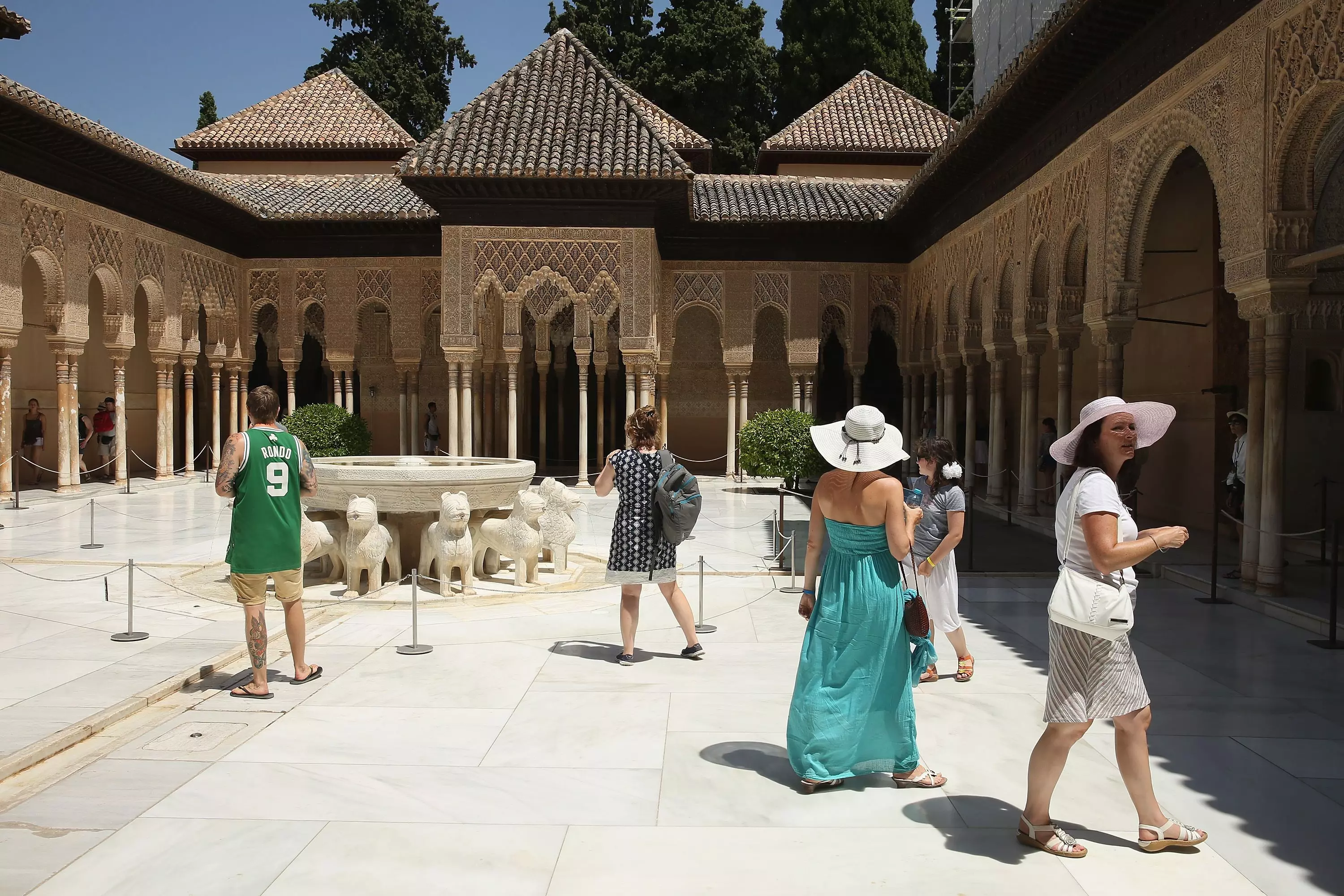 dziedziniec otoczony rzeźbionymi kolumnami prowadzący do pałaców, rzeźba fontanna z lwami pośrodku, Alhambra Turyści mieszają się