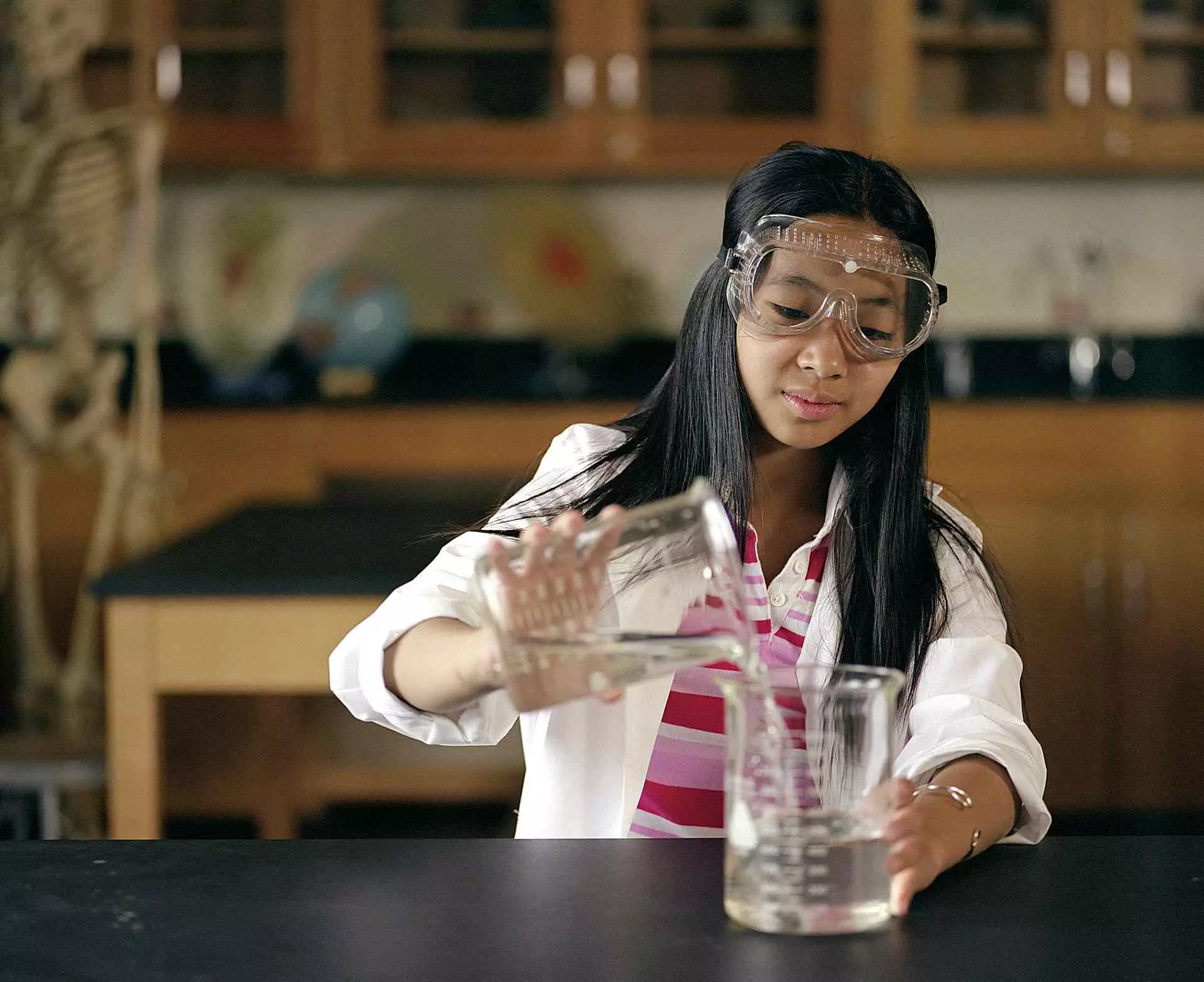 女孩（12-14 岁）戴着护目镜，做化学实验