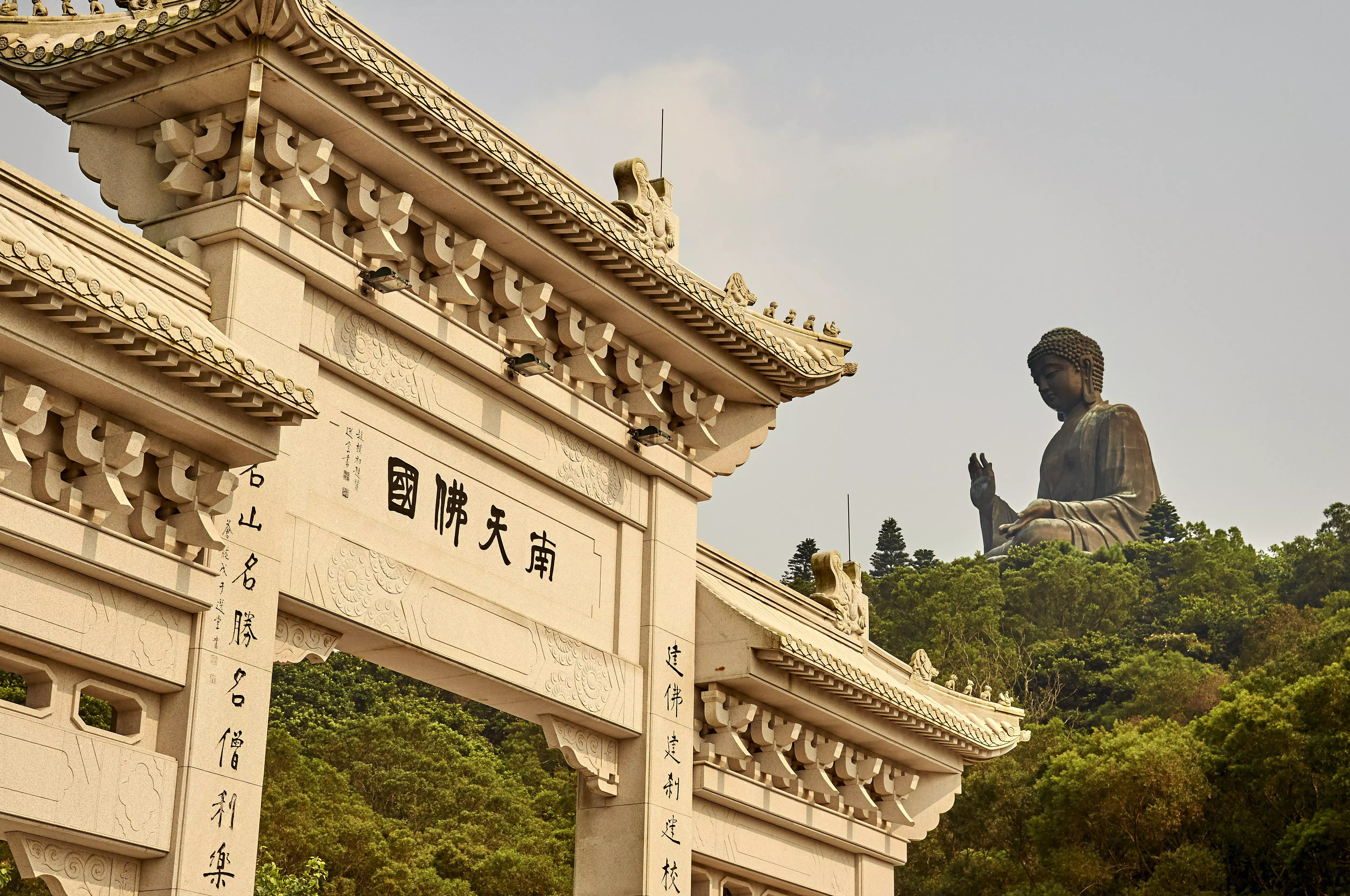 Κινεζική είσοδος σε πρώτο πλάνο και τεράστιο άγαλμα στο παρασκήνιο