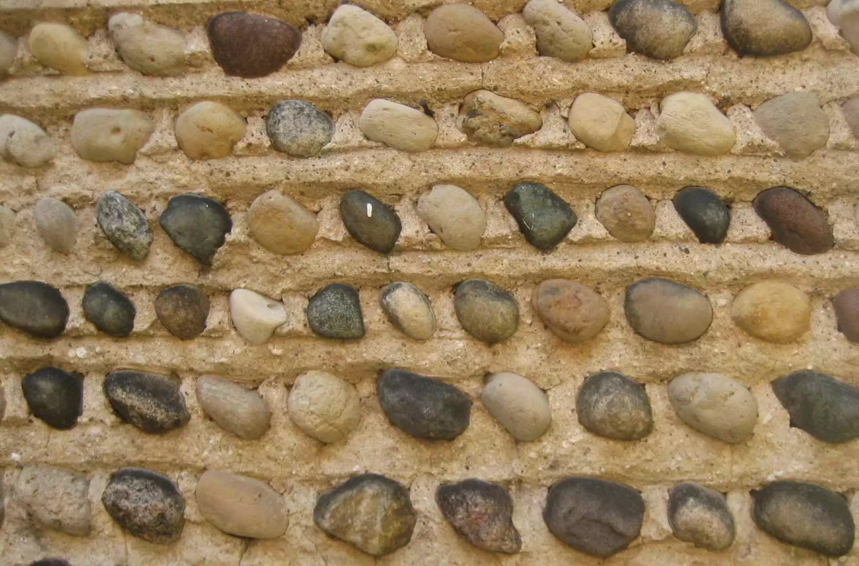 lähivõte maja vooderdist, suured horisontaalsed sooned kividega inkrusteeritud