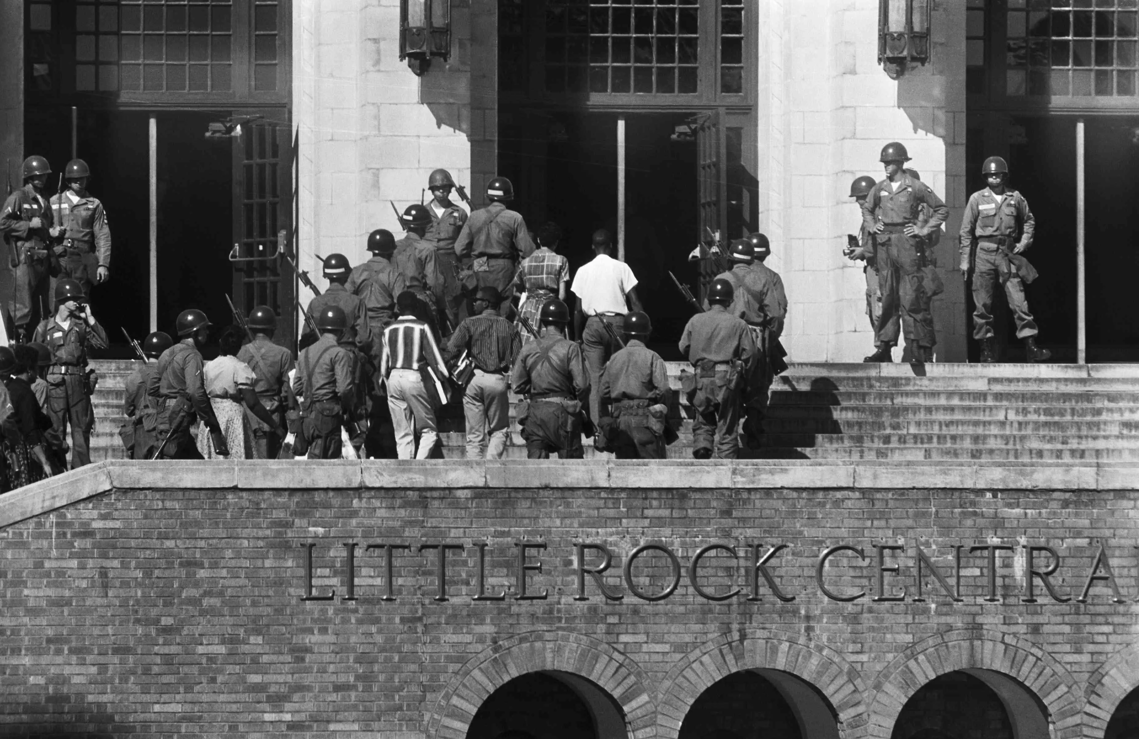 Afro-Amerikaanse studente word deur Amerikaanse soldate beskerm wanneer hulle Little Rock Central High School binnegaan