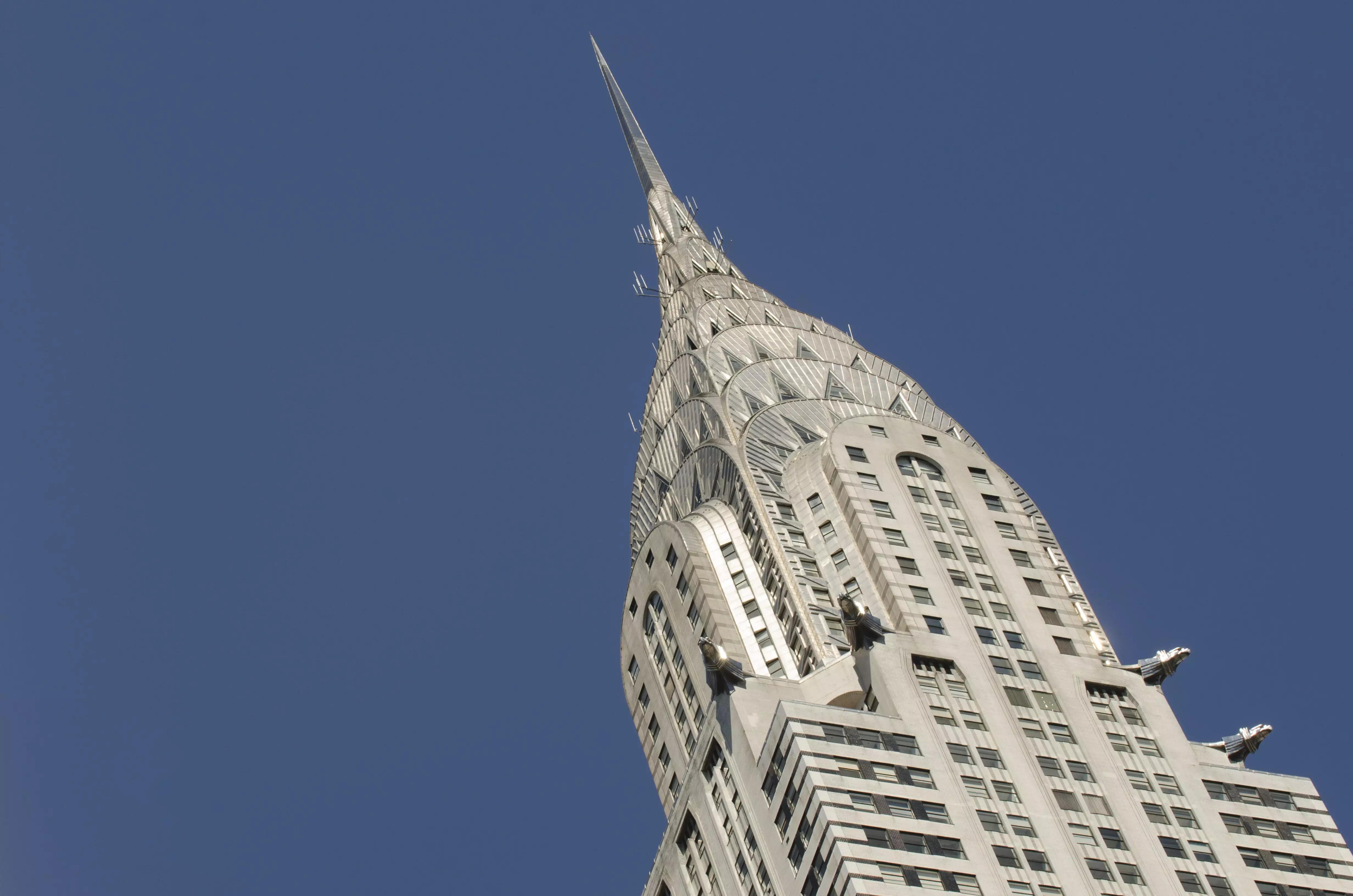 detalle de la parte superior escalonada del rascacielos con extensión superior en forma de aguja y ornamentación plateada debajo