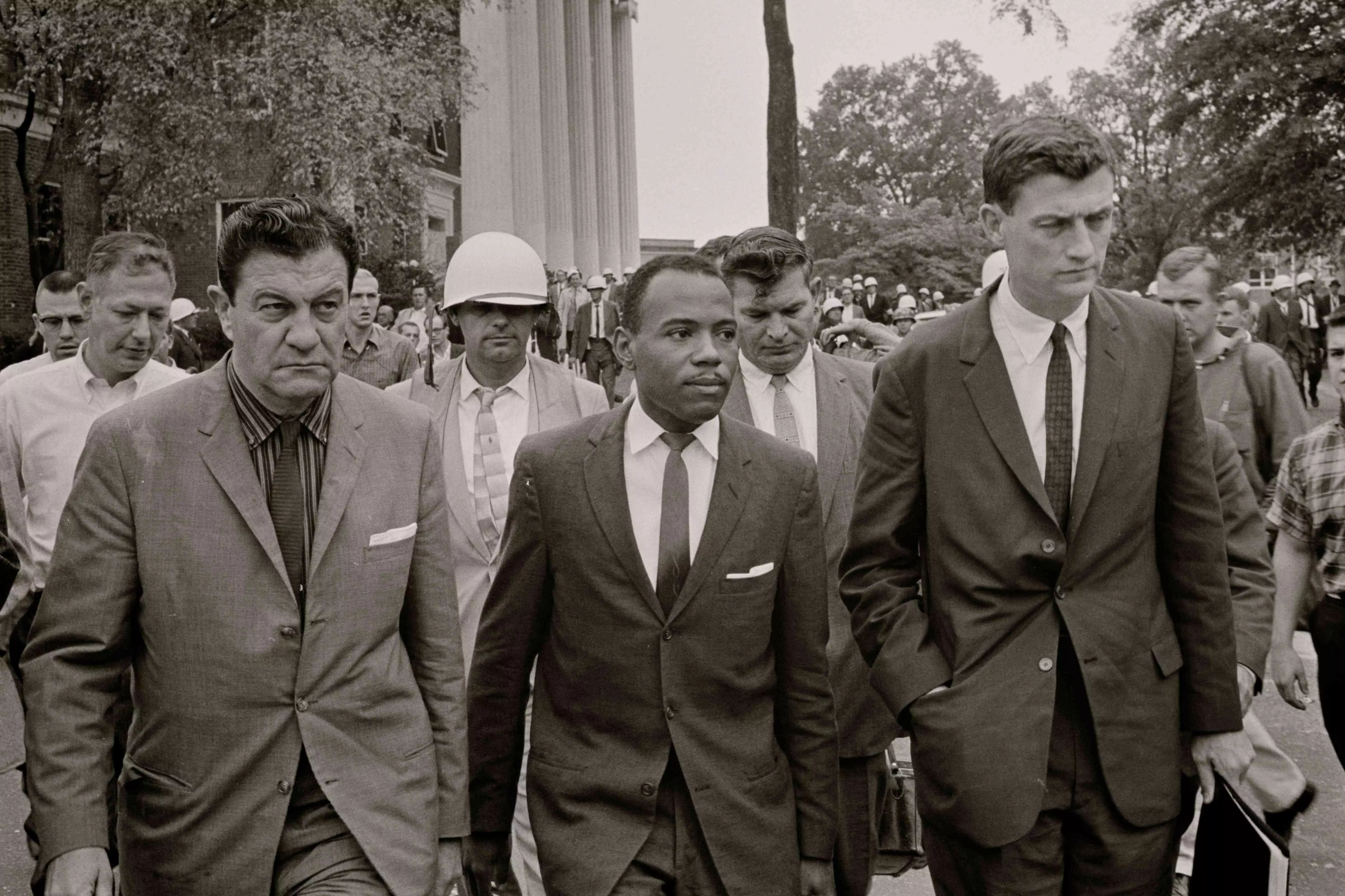 James Meredith cammina con due uomini accanto a lui e una folla di persone dietro di lui