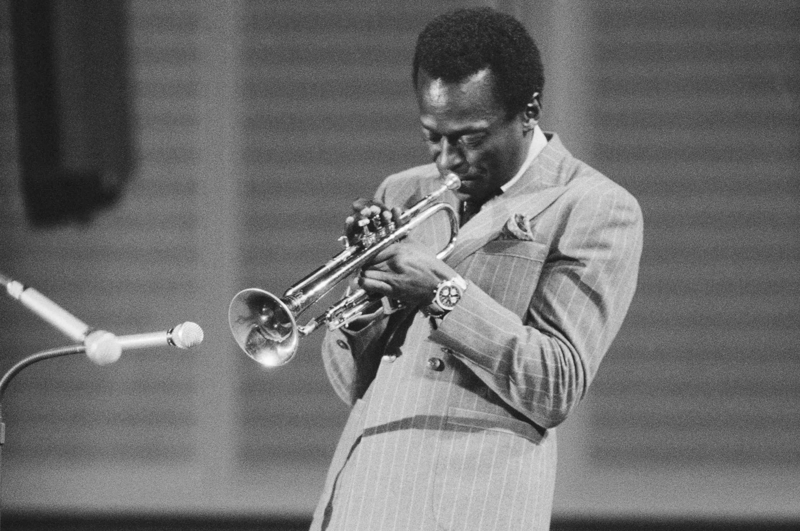 Mae Miles Davis yn canu trwmped i feicroffon