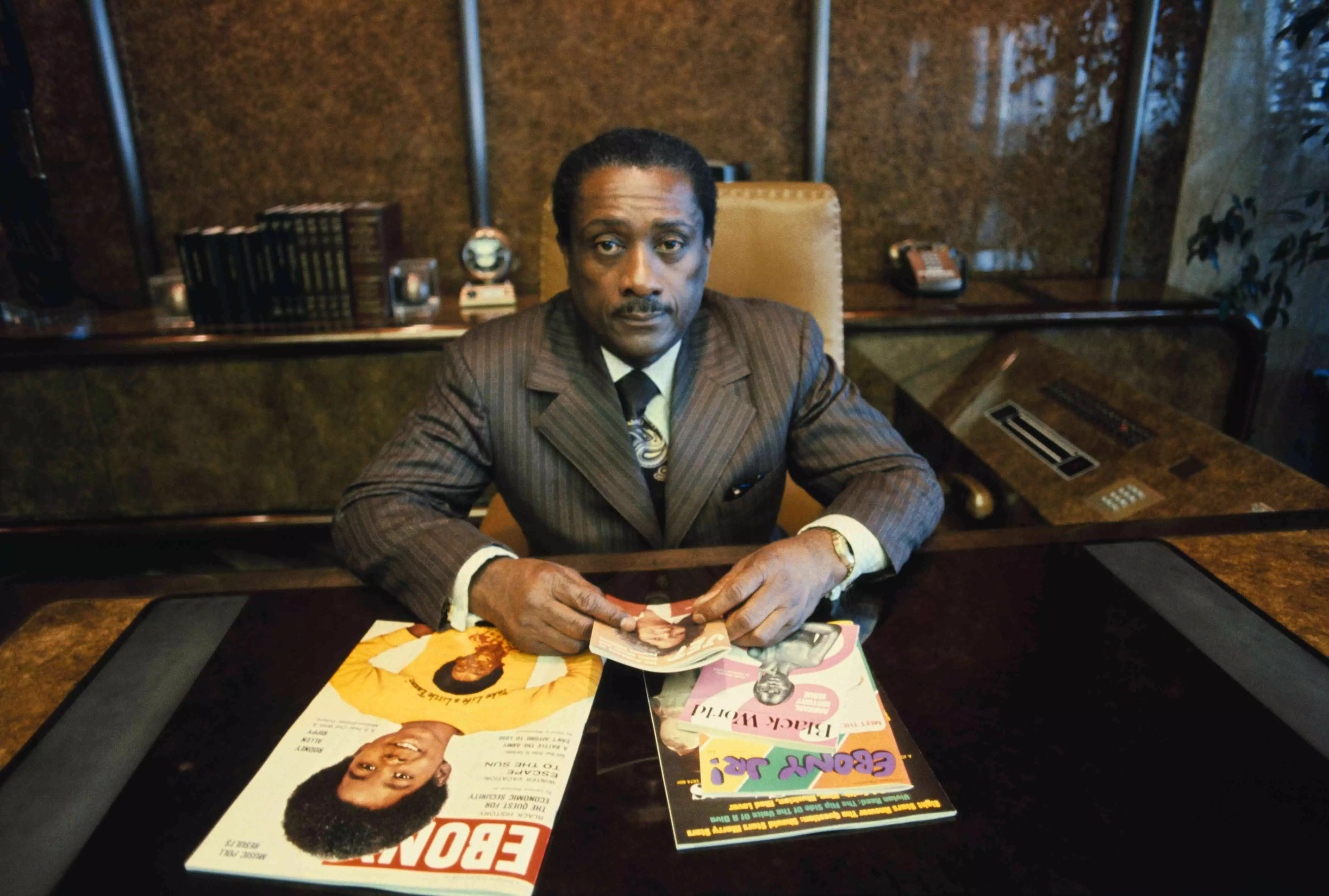 Ο John Harold Johnson κάθεται στο γραφείο του με ένα αντίγραφο του Ebony και του Ebony Jr.