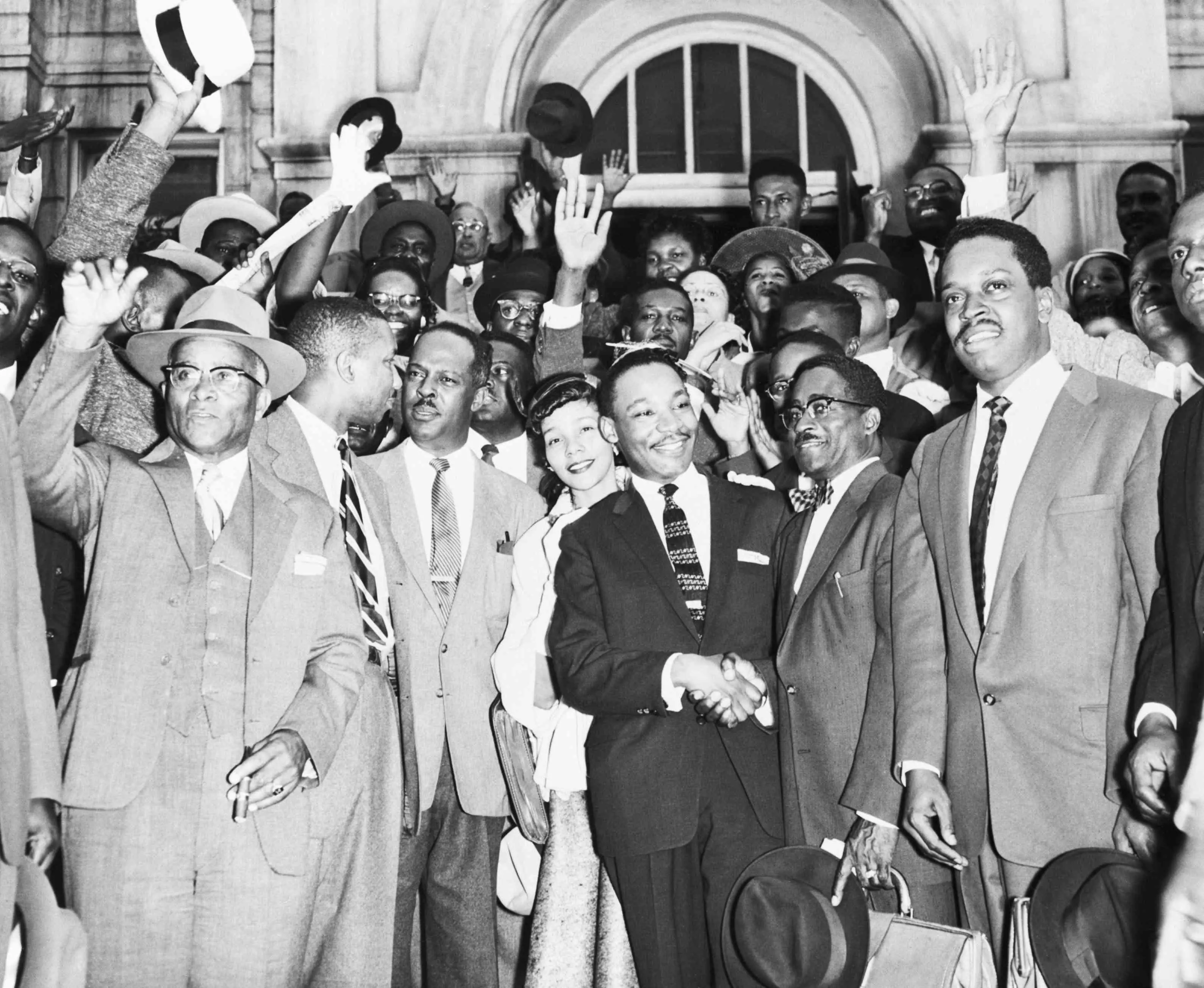 डॉ मार्टिन लूथर किंग जूनियर समर्थकों की भीड़ से घिरे हुए मुस्कुराते हुए कोर्टहाउस के बाहर खड़े हैं