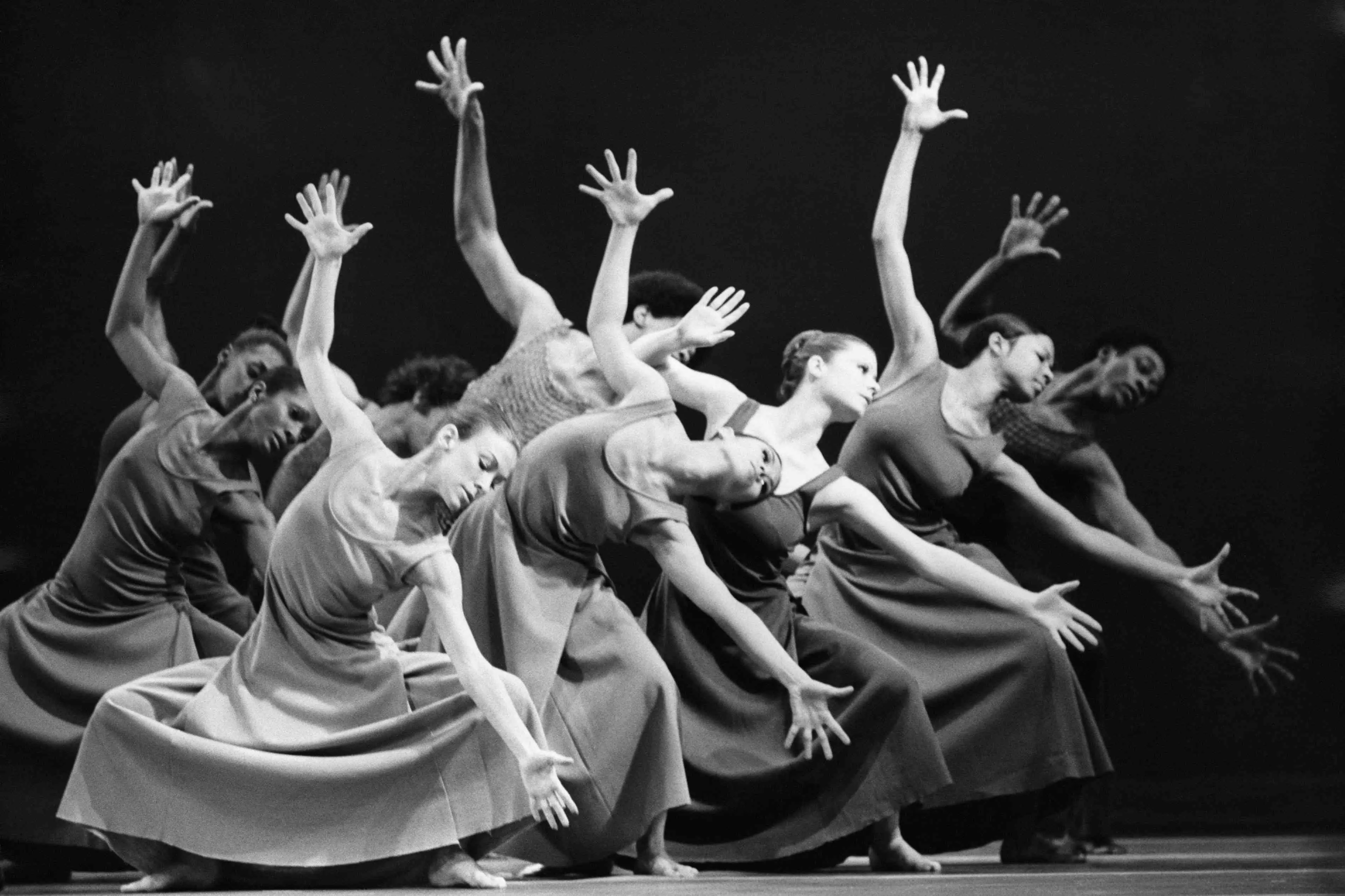 Alvin Ailey Amerikas dejas teātra dejotāji uzstājas ar izplestām rokām