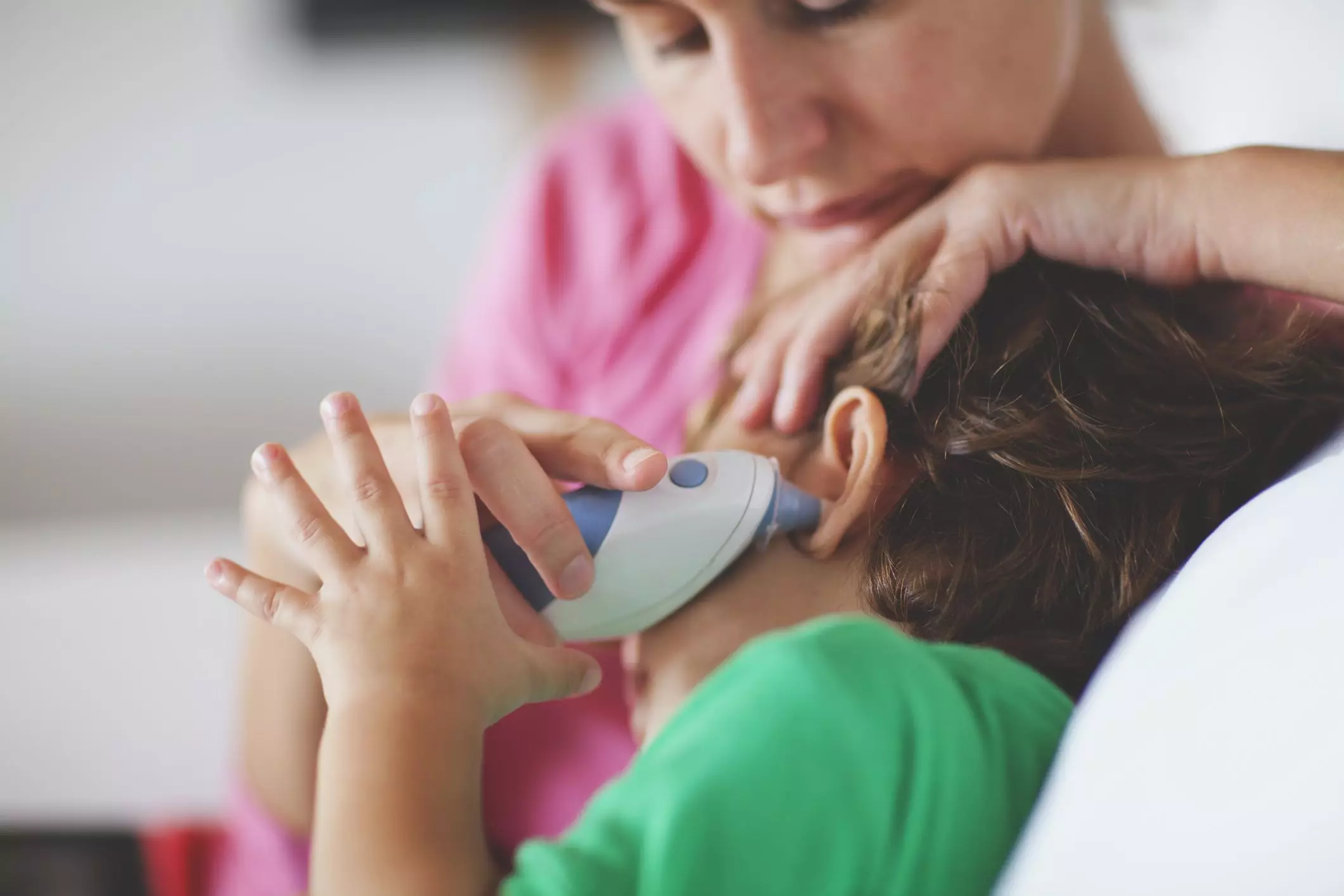 Mamma tar ung pojke temperatur med örontermometer