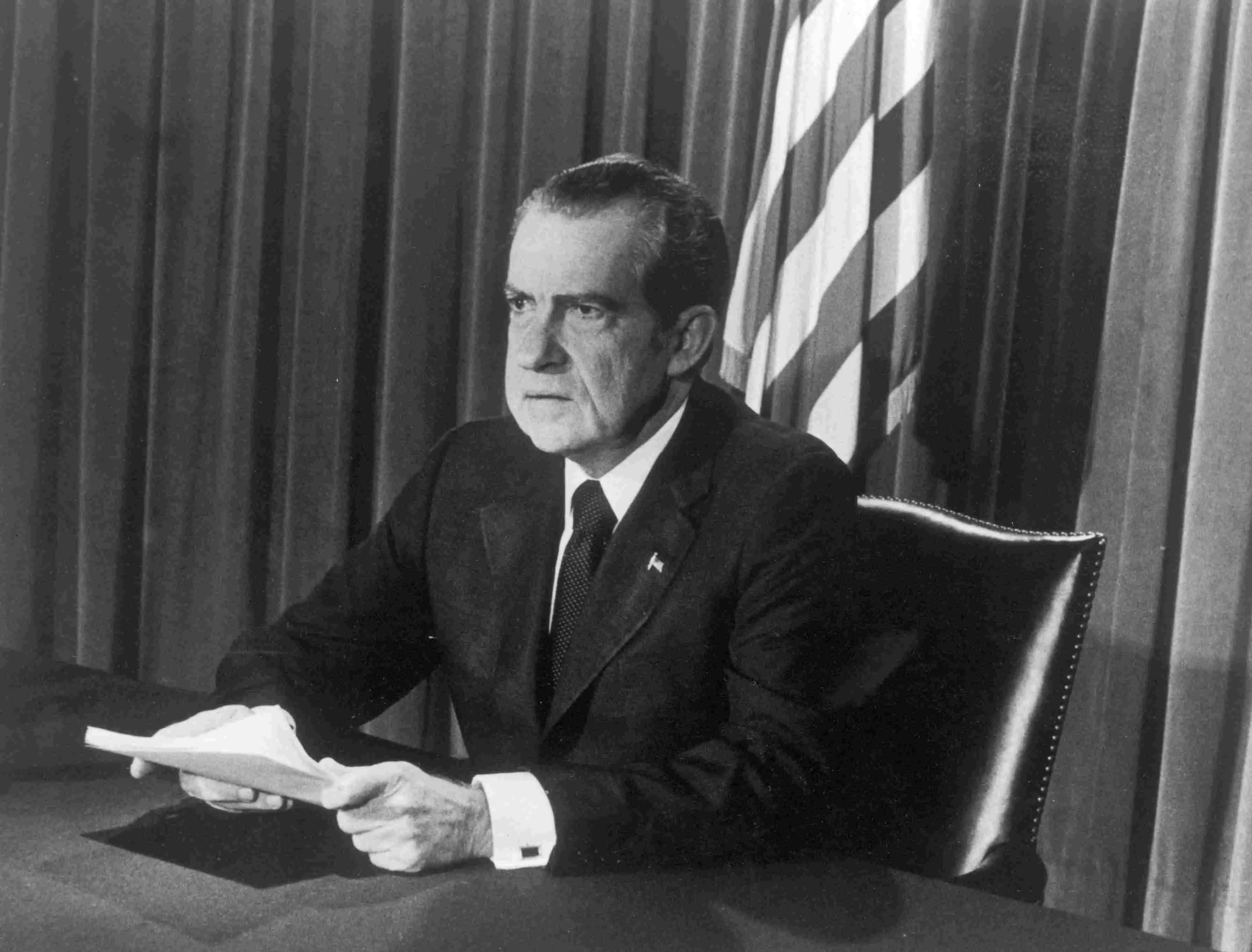 Ààrẹ Richard Nixon jókòó síbi tábìlì rẹ̀ bí ó ṣe ń kéde ìfipòsílẹ̀ rẹ̀.