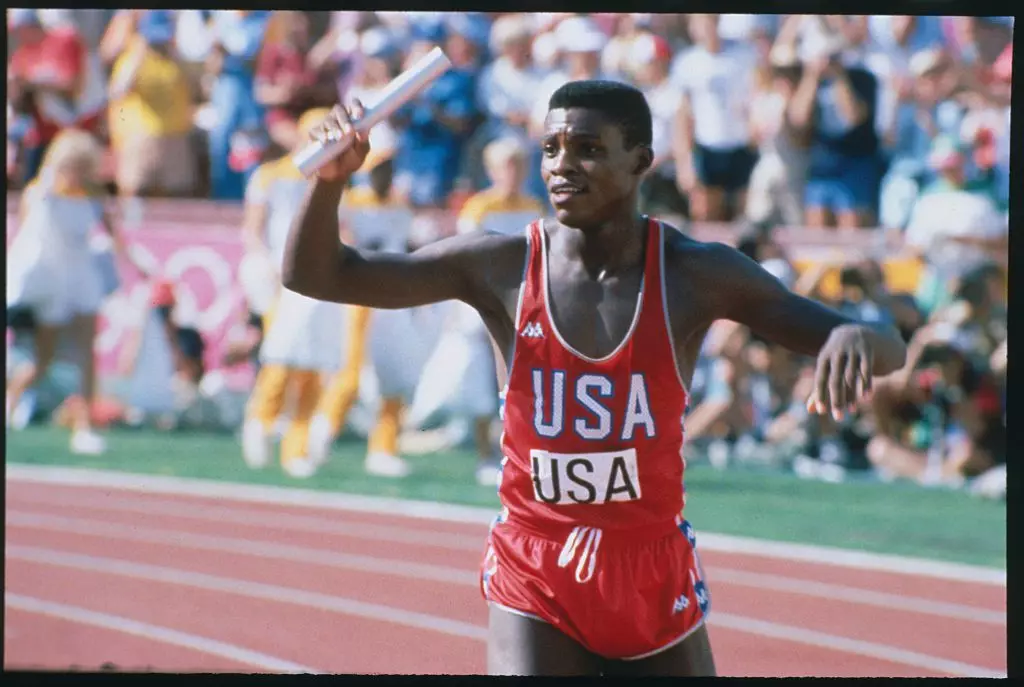 1984年のオリンピックでレースに勝った後、カール・ルイスが腕を上げる